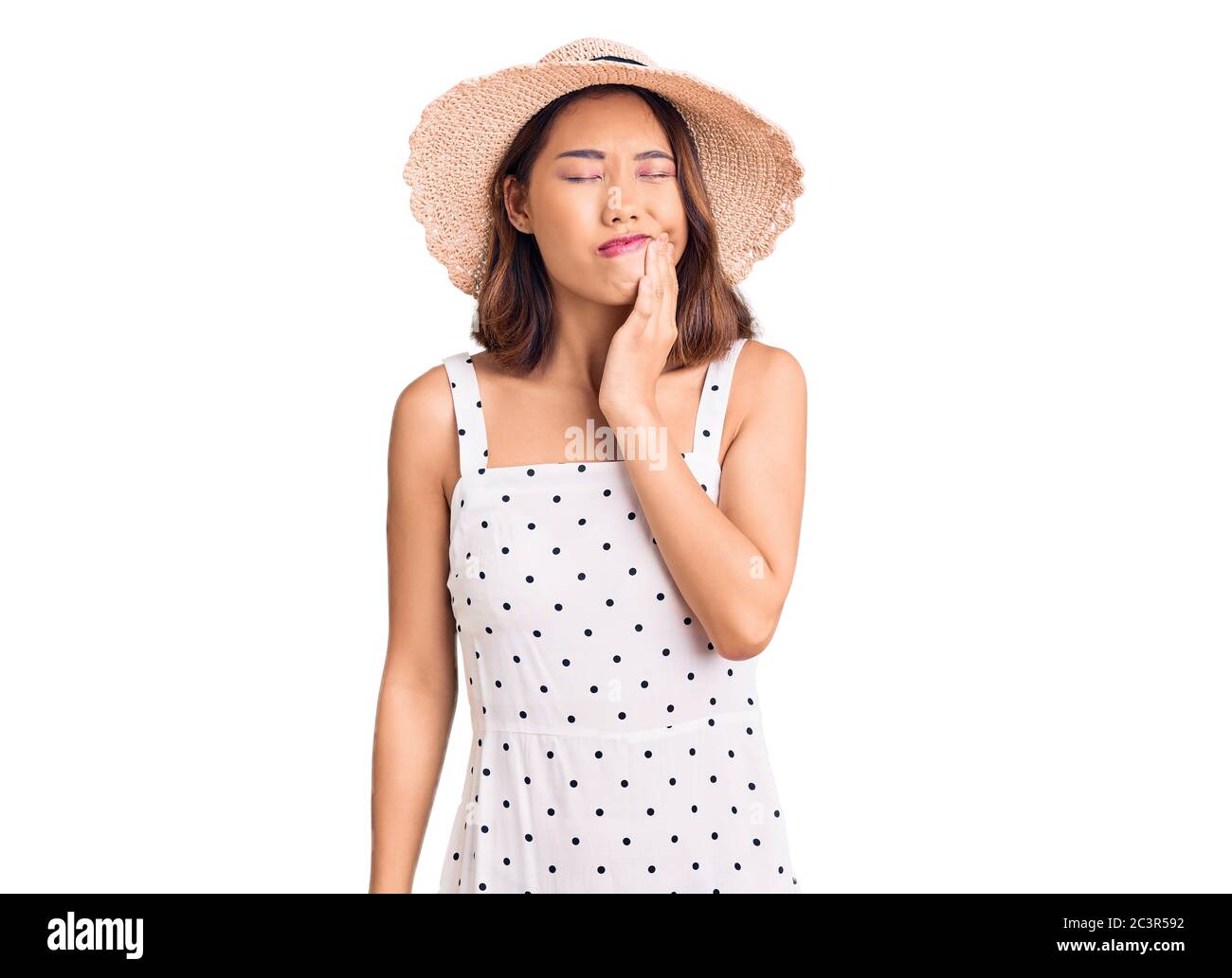Young beautiful chinese girl wearing summer hat touching mouth with ...