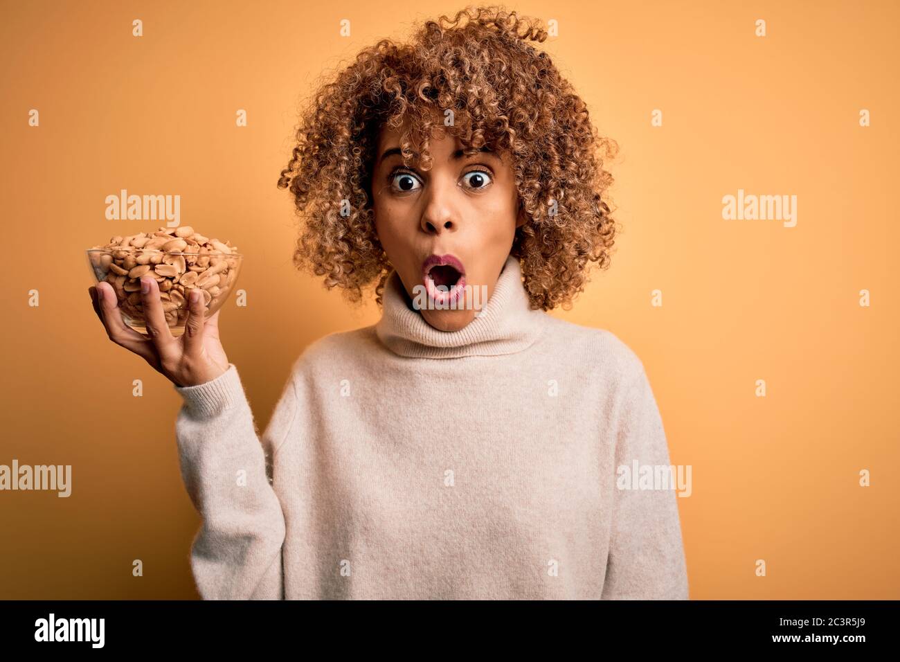 Young african american woman with curly hair holding bowl with healthy ...