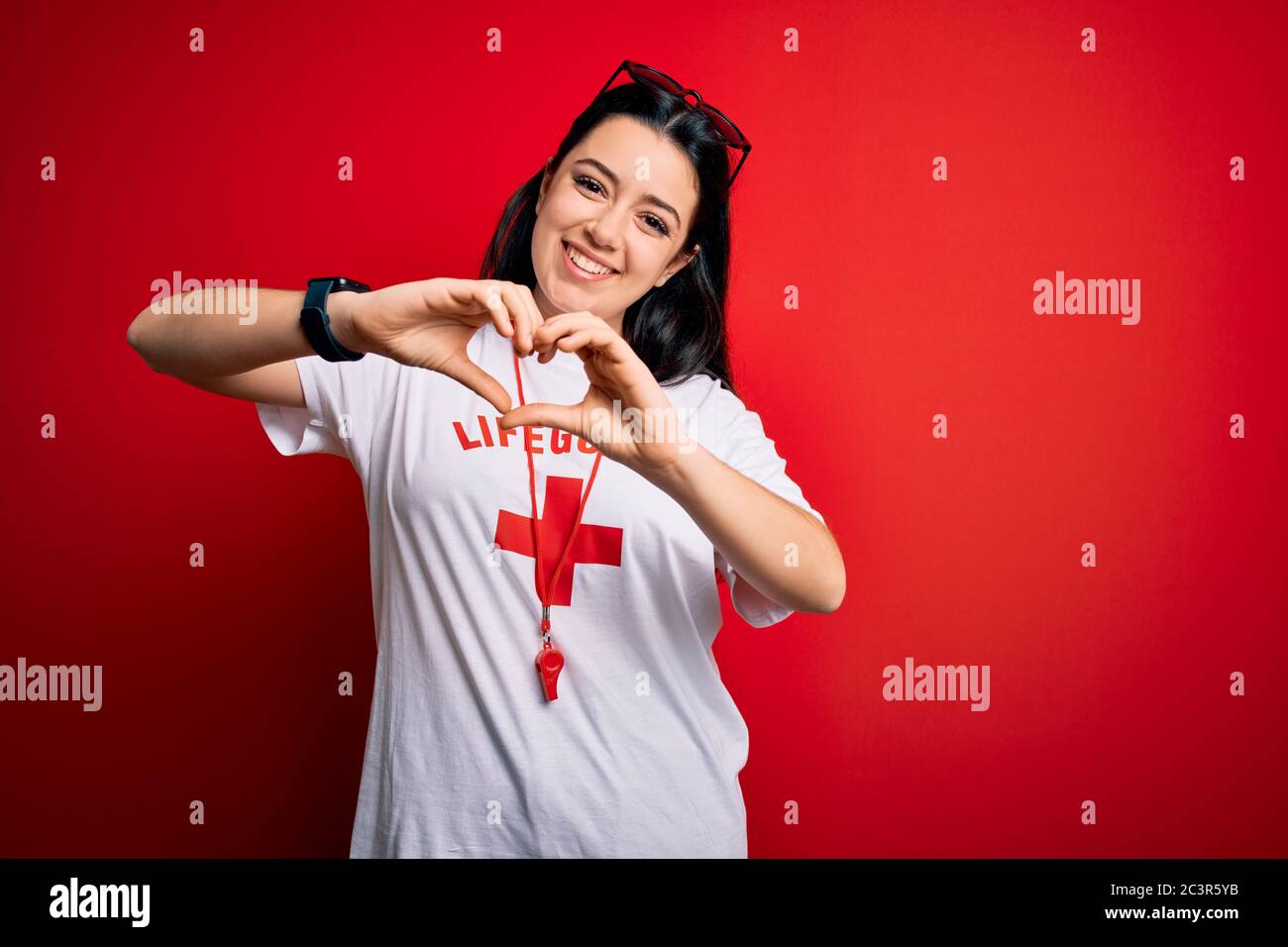 Young lifeguard woman wearing secury guard equipent over red background ...