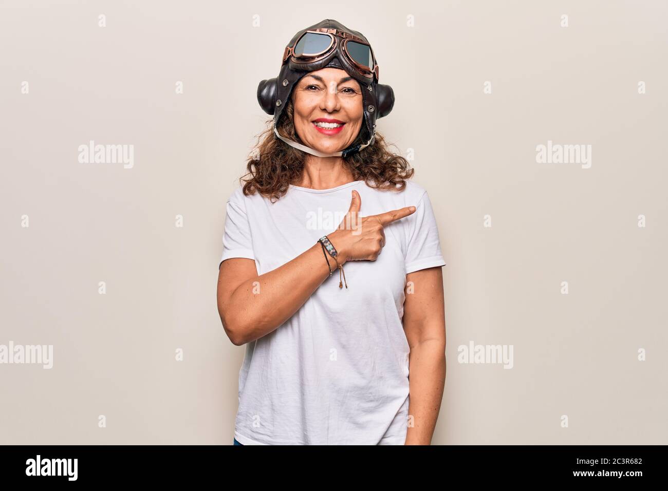 Middle age brunette woman wearing goggles and retro aviator leather hat ...