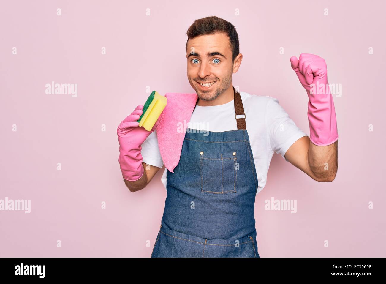 Young cleaner man with blue eyes cleaning wearing apron and gloves ...