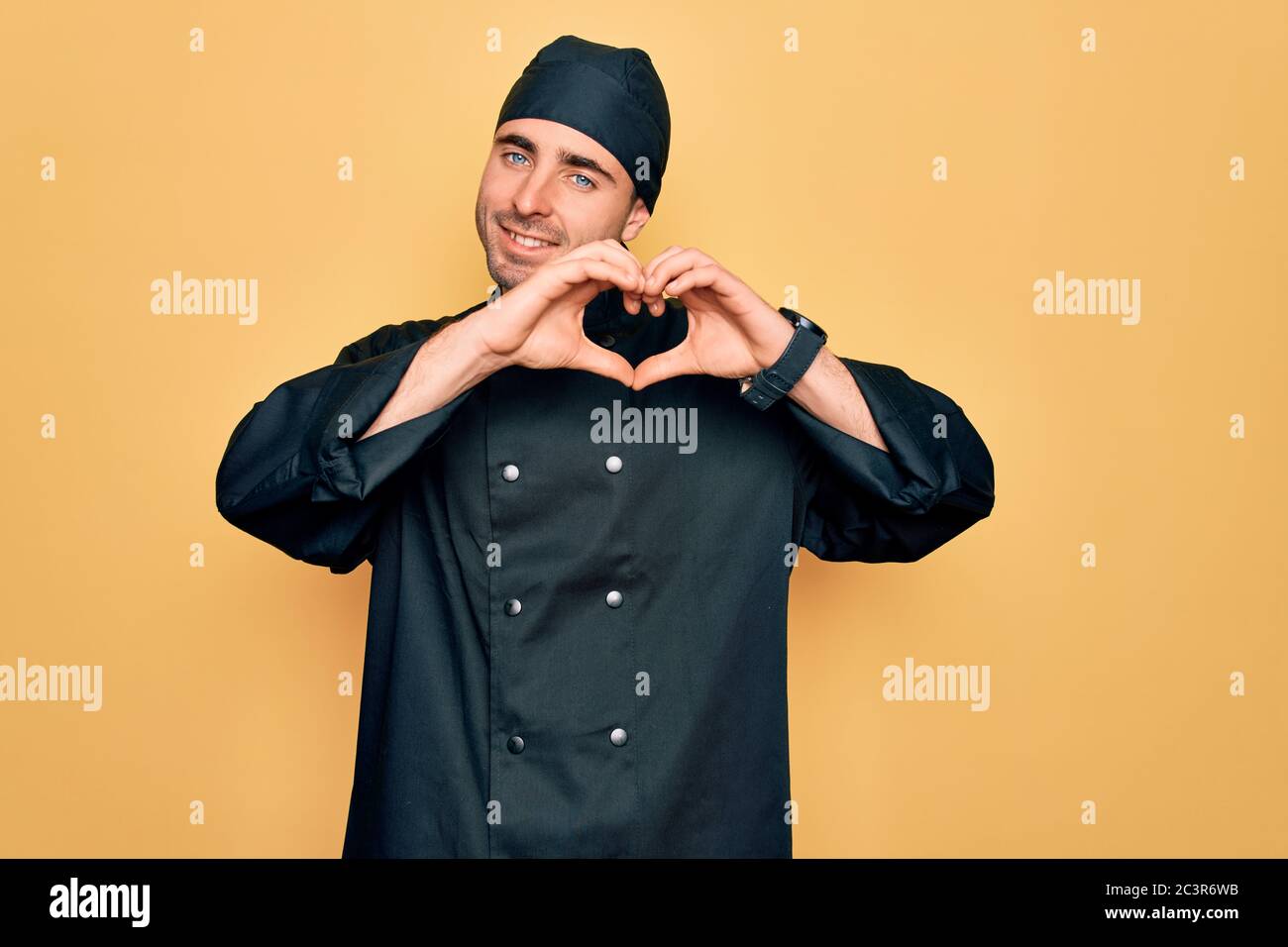 Young handsome cooker man with blue eyes wearing uniform and hat over ...