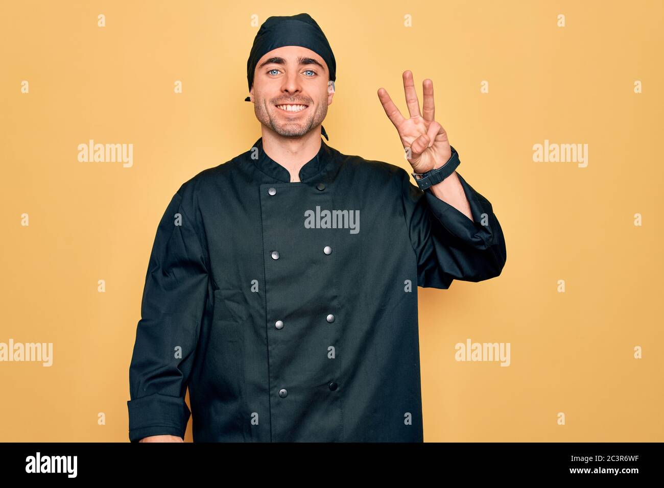 Young handsome cooker man with blue eyes wearing uniform and hat over ...
