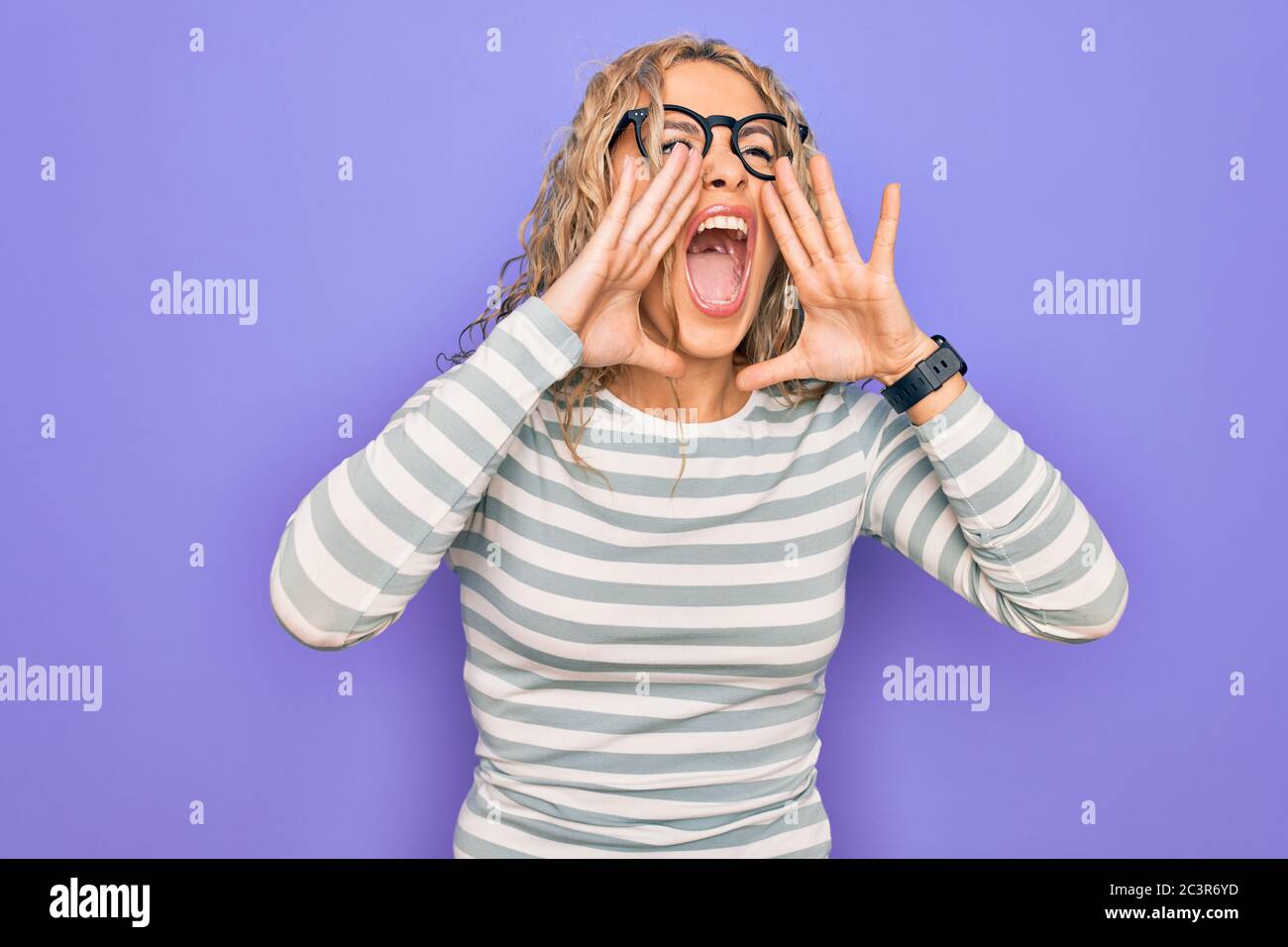 Beautiful blonde woman wearing casual striped t-shirt and glasses over ...