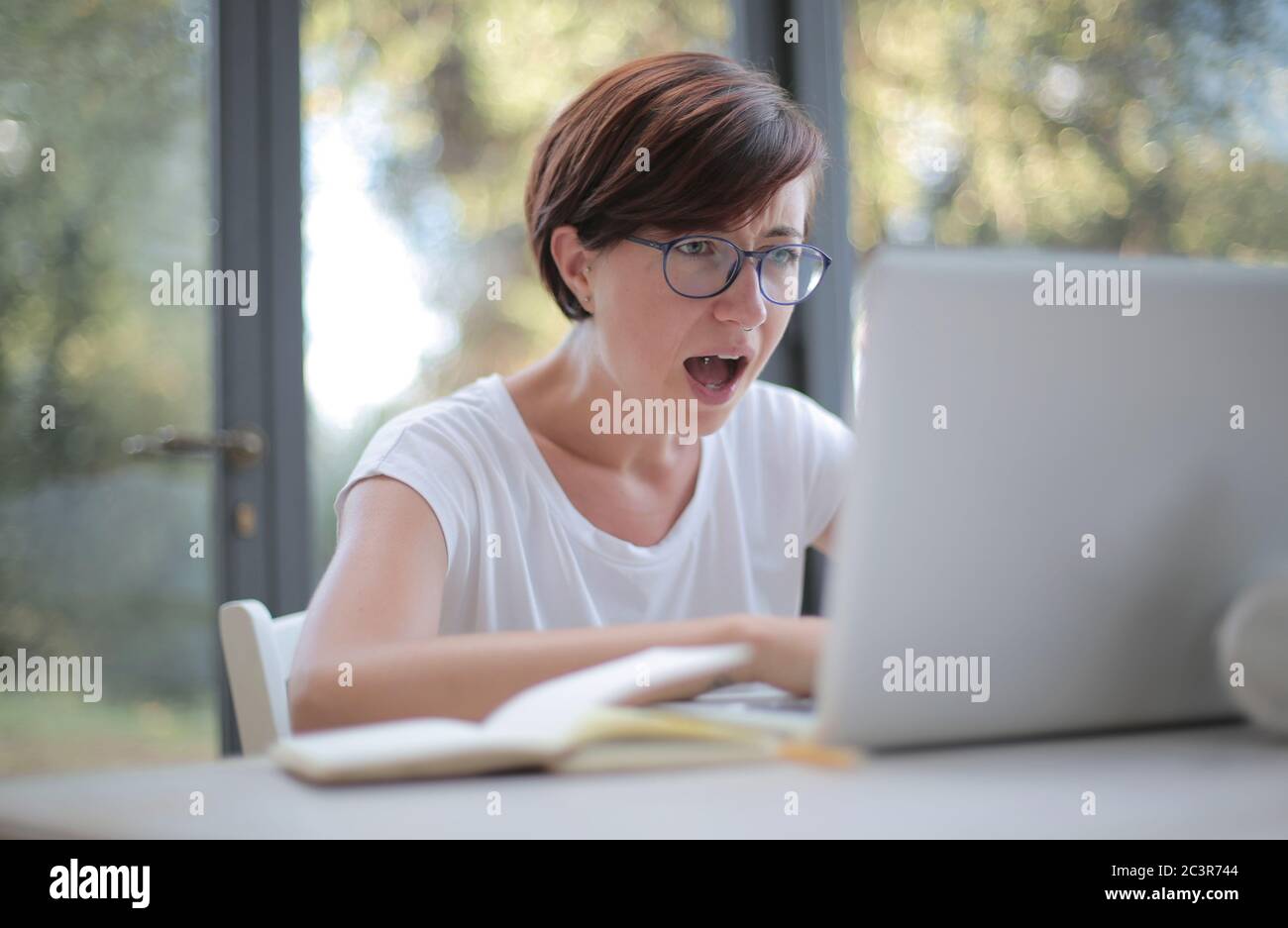 Lady with an open mouth in front of her laptop showing the emotion of ...