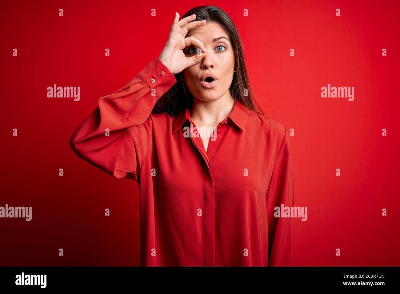 Young beautiful woman with blue eyes wearing casual shirt standing over ...