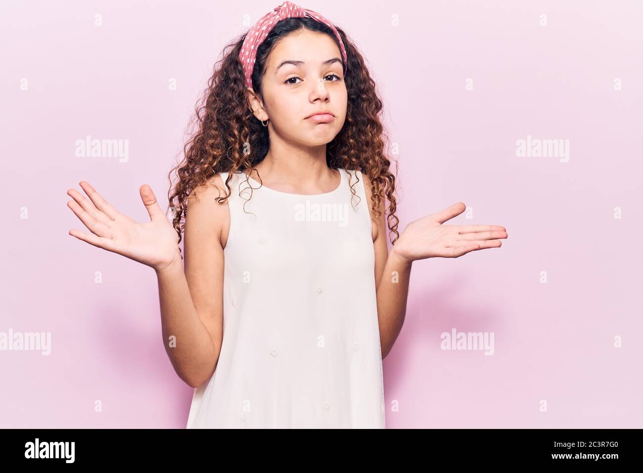 Beautiful kid girl with curly hair wearing casual clothes clueless and ...