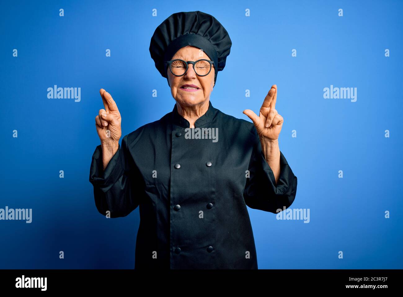 Senior beautiful grey-haired chef woman wearing cooker uniform and hat ...