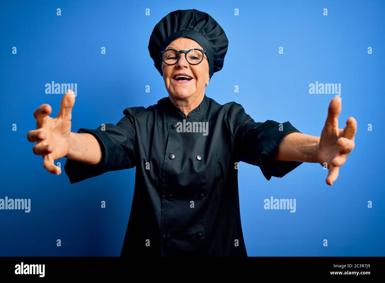 Senior beautiful grey-haired chef woman wearing cooker uniform and hat ...