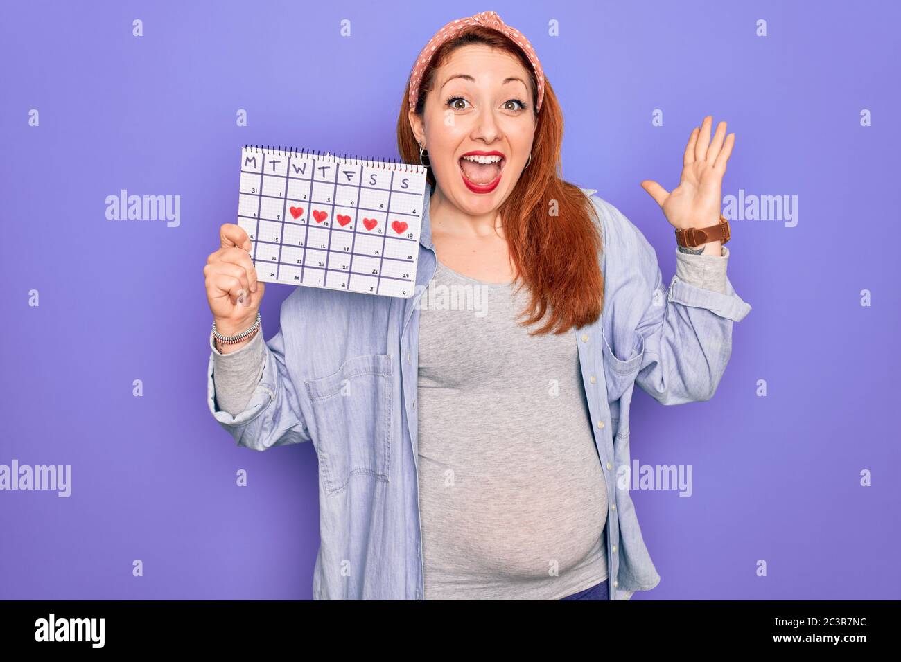 Young beautiful redhead pregnant woman expecting baby holding period ...