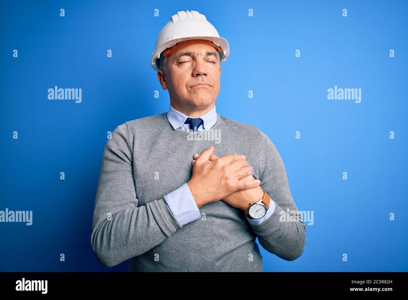 Middle age handsome grey-haired engineer man wearing safety helmet over ...
