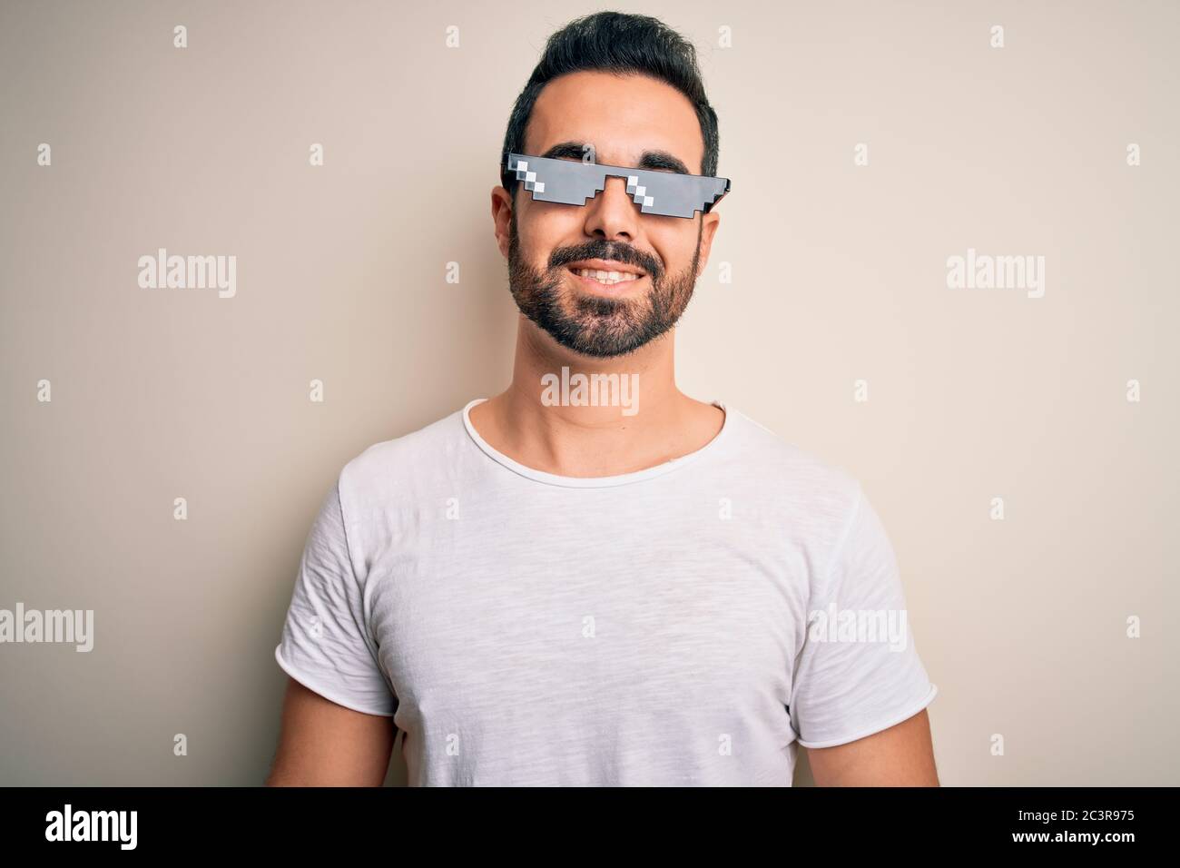 Young handsome man with beard wearing funny thug life sunglasses over ...