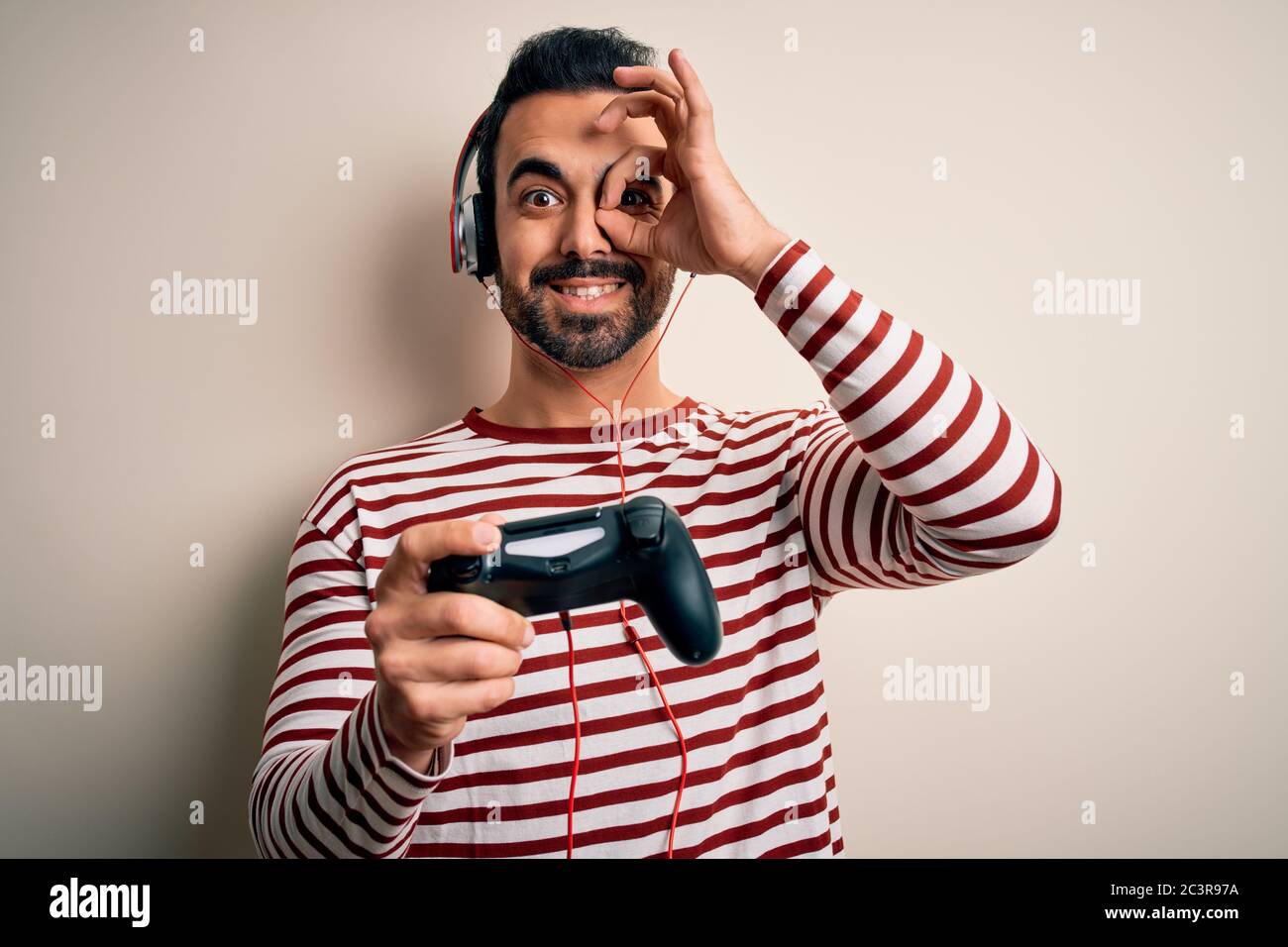 Young handsome gamer man with beard playing video game using joystick ...