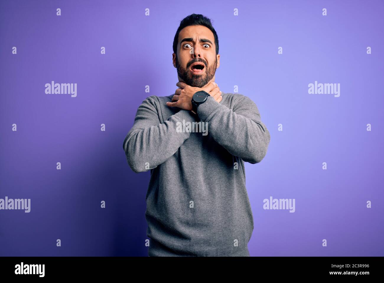 Handsome businessman with beard wearing casual tie standing over purple ...