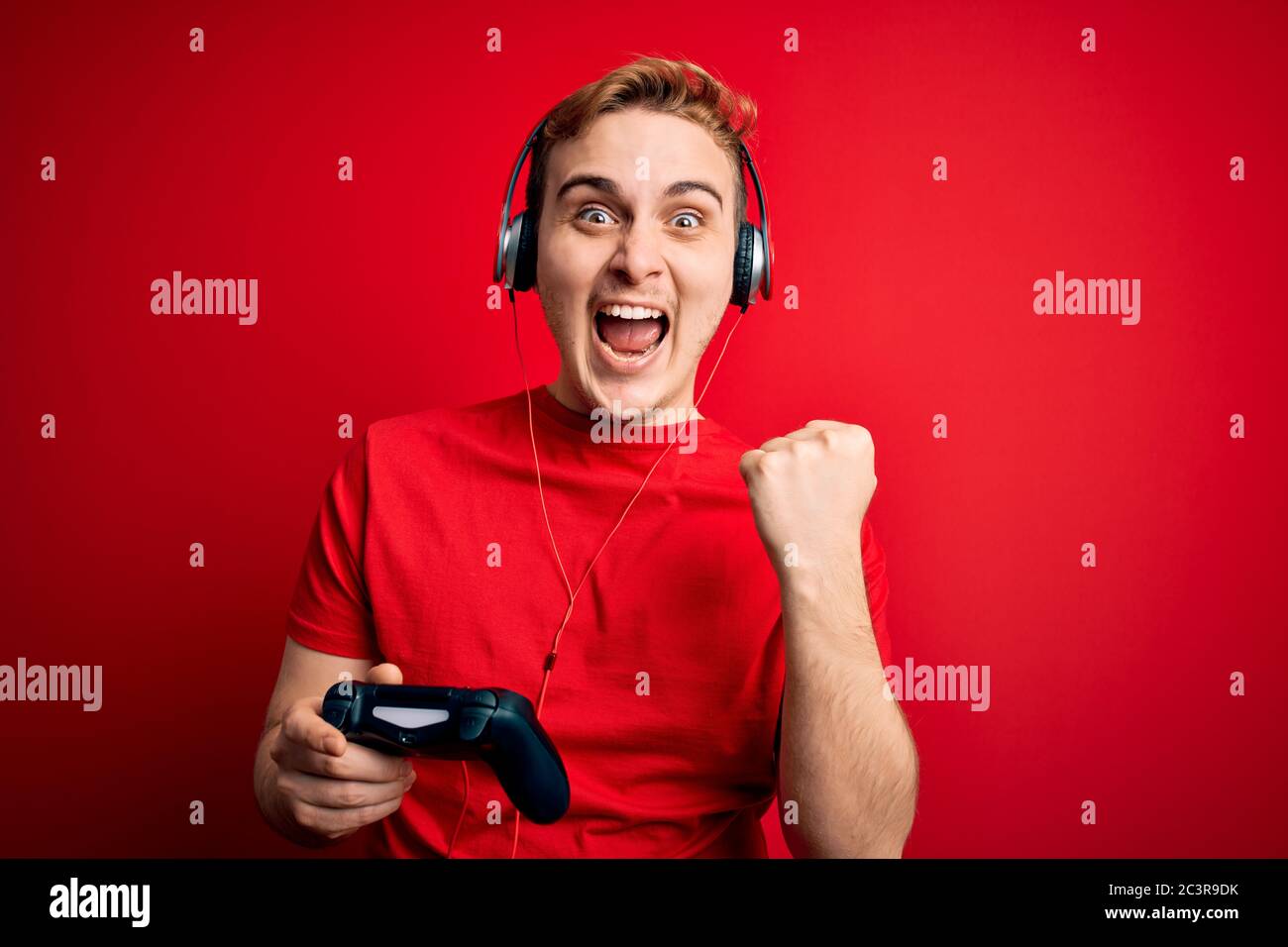 Young handsome redhead gamer man playing video game using headphones ...