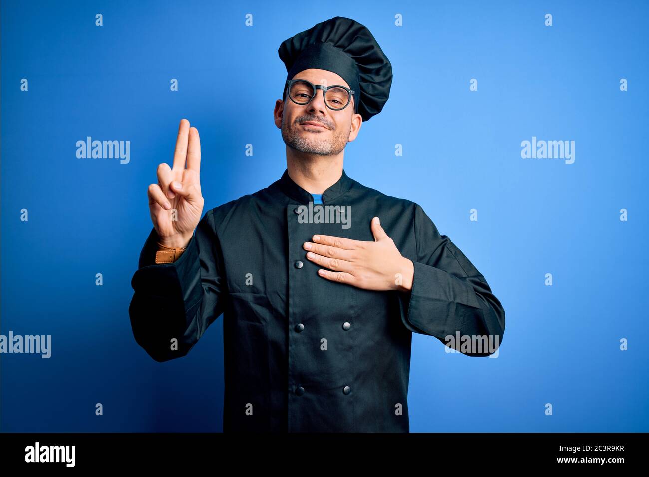 Young handsome chef man wearing cooker uniform and hat over isolated ...