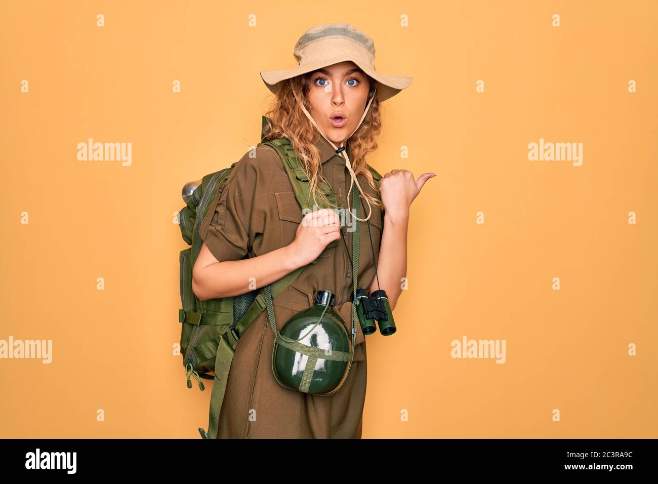 Young blonde explorer woman with blue eyes hiking wearing backpack and ...