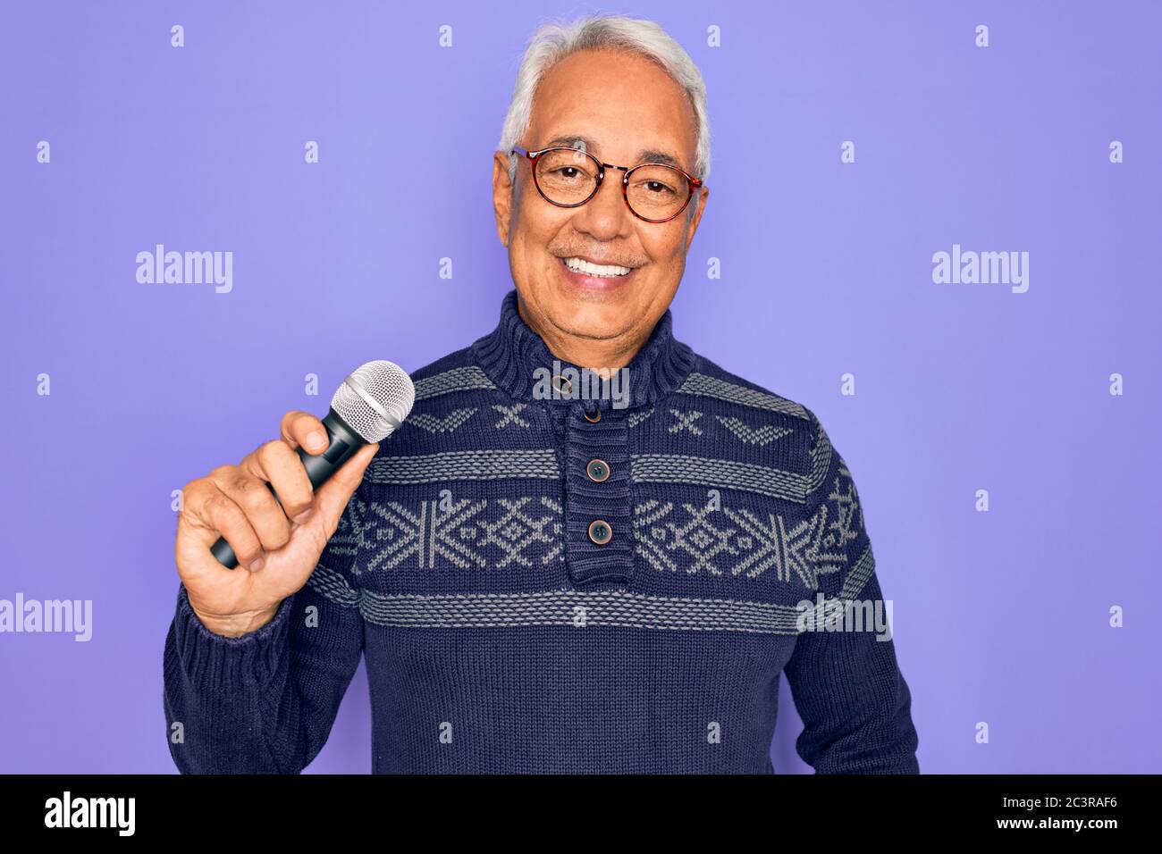 Middle age senior grey-haired singer man singing using music microphone ...