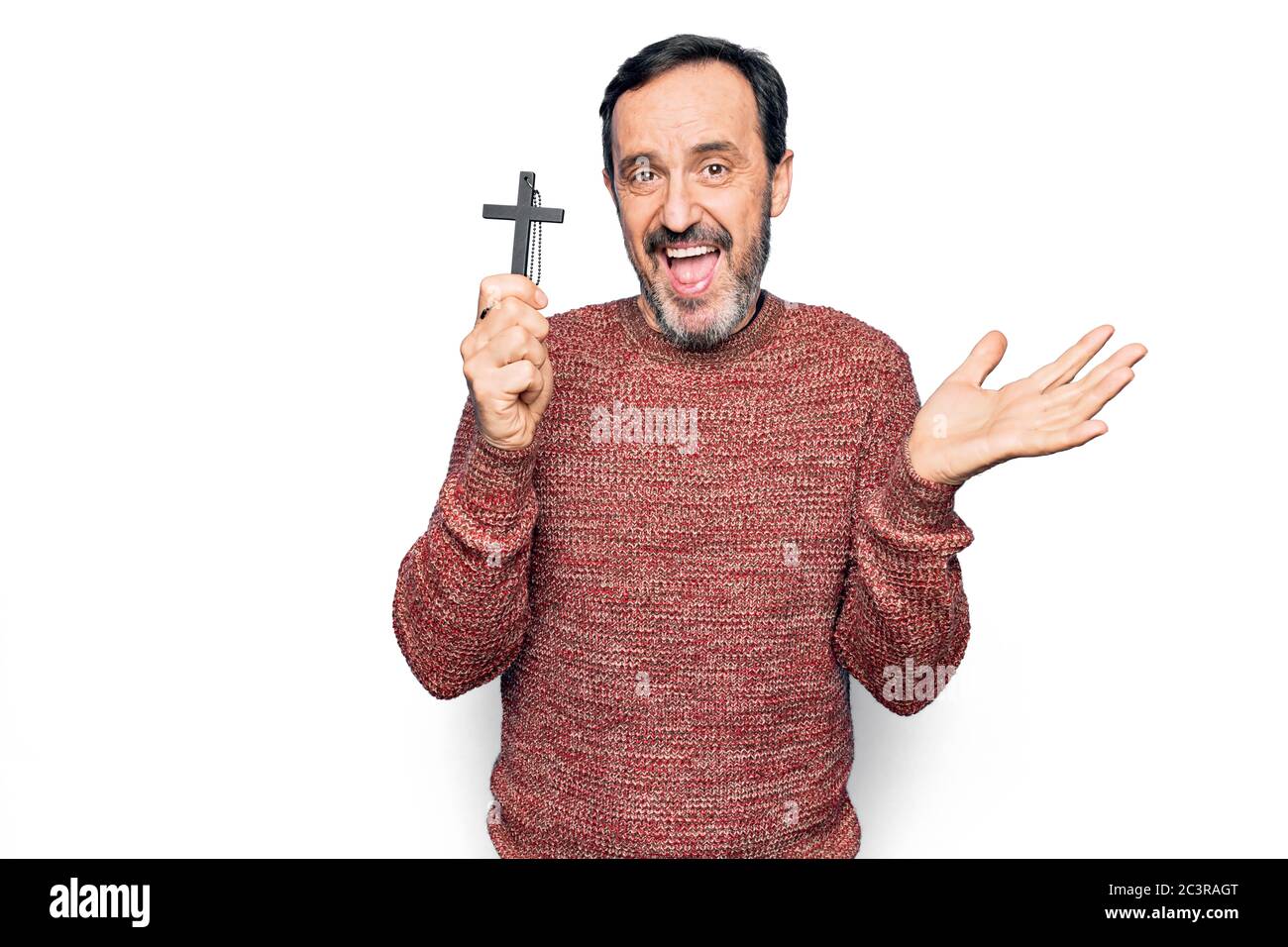 Middle age handsome catholic man praying holding christian cross over ...