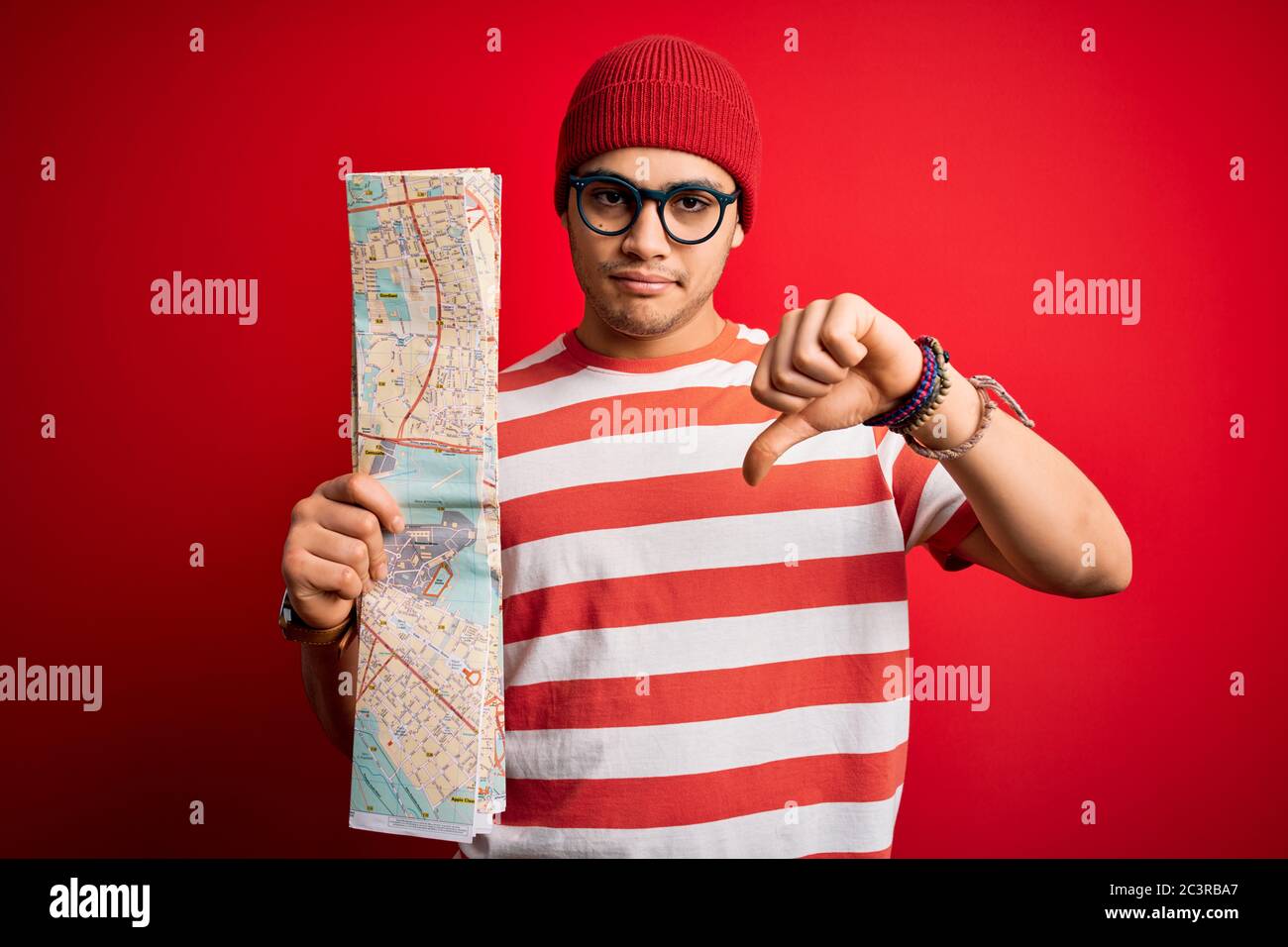 Young brazilian tourist man on vacation holding city map over isolated ...