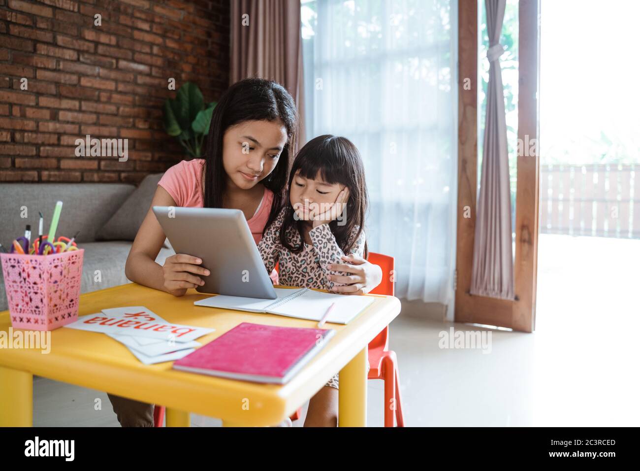 upset kid while studying at home with her big sister at home. bored ...