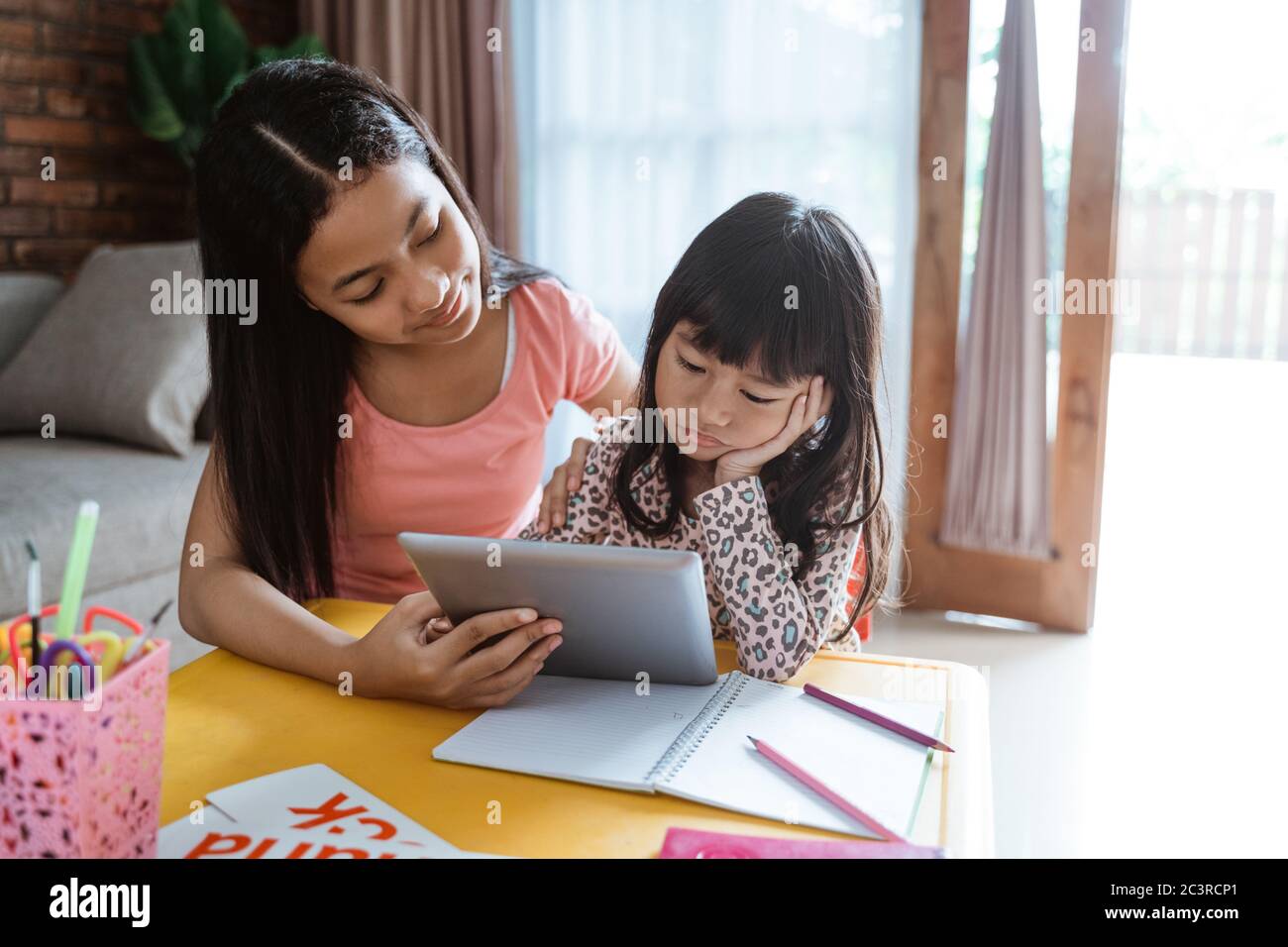 upset kid while studying at home with her big sister at home. bored ...