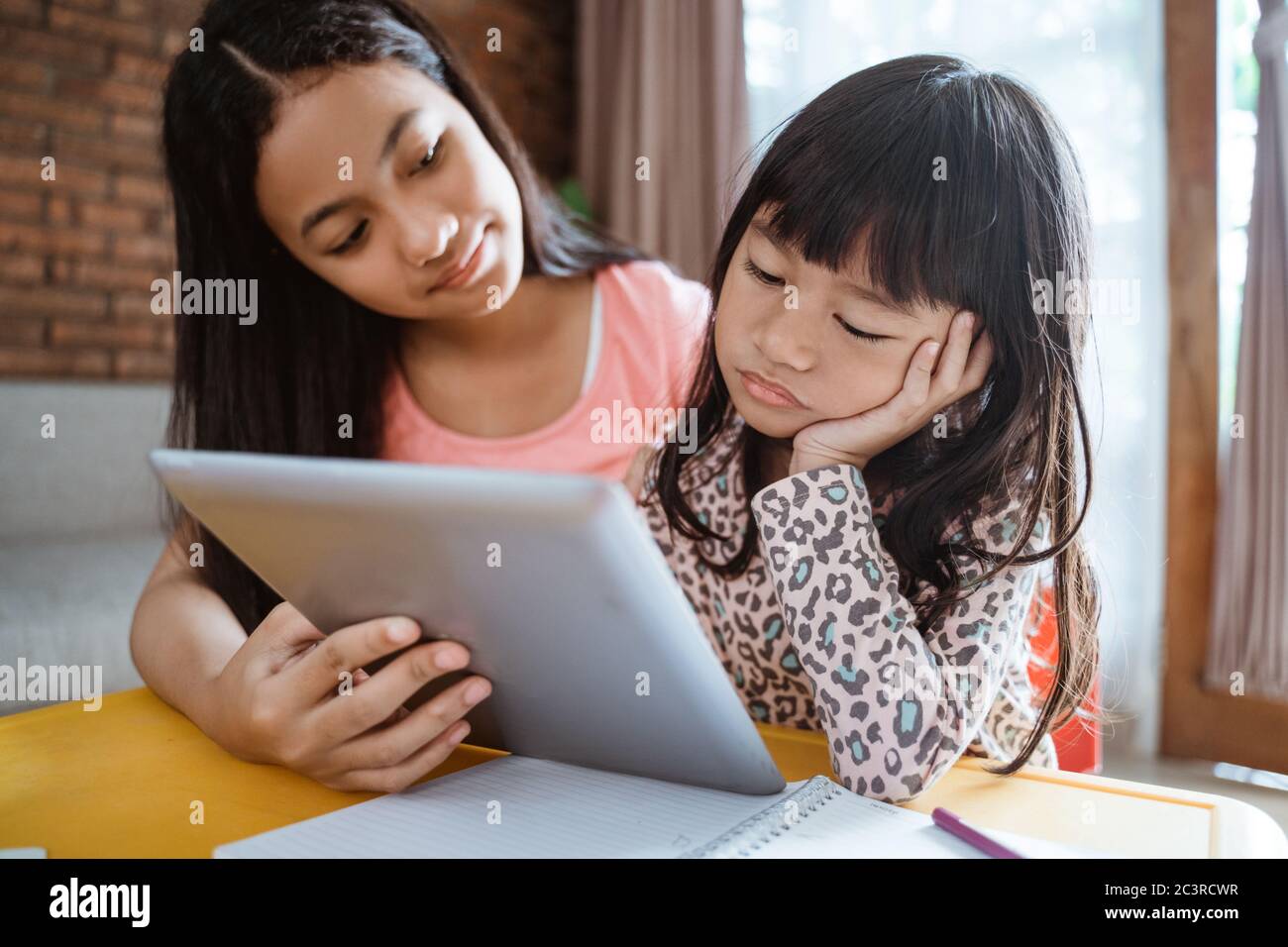 upset kid while studying at home with her big sister at home. bored ...