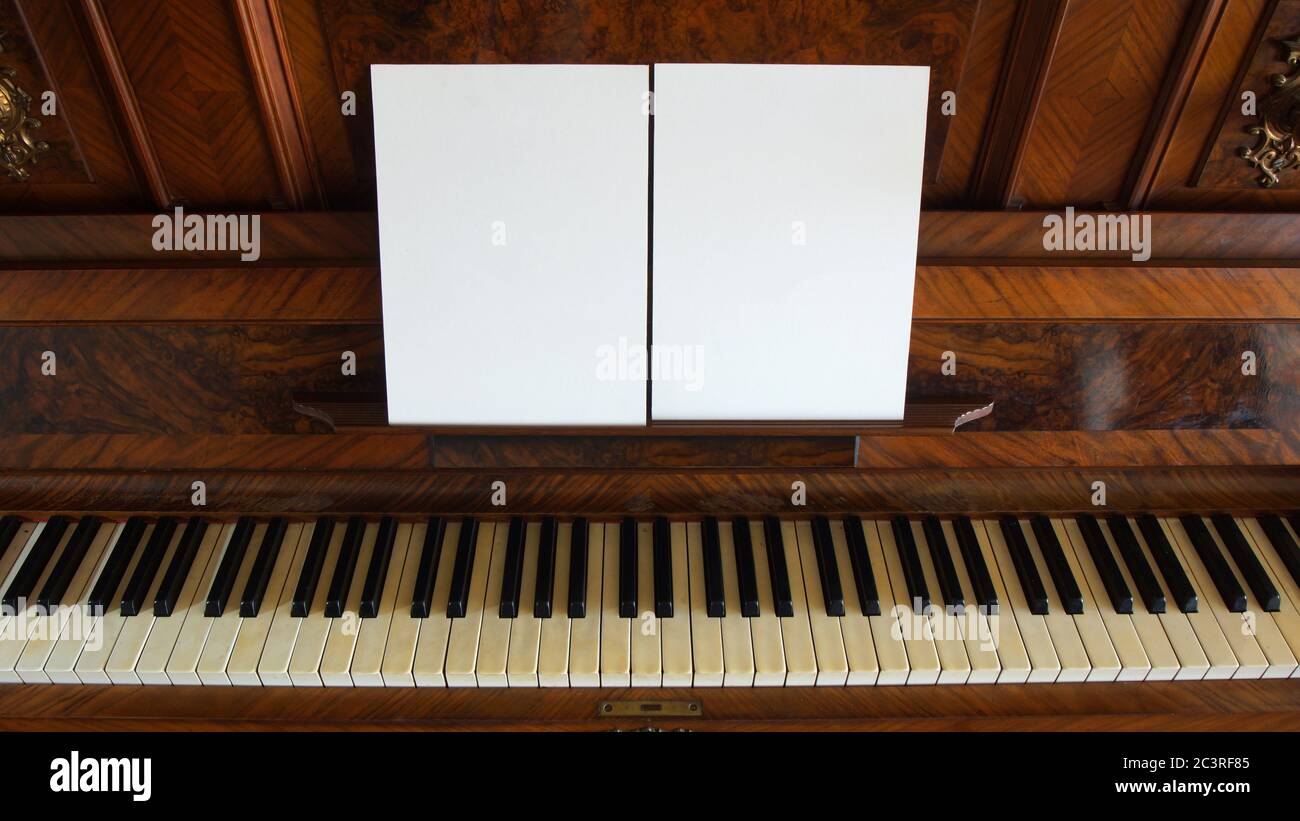 Front view of an antique wooden piano with the keyboard open and two ...
