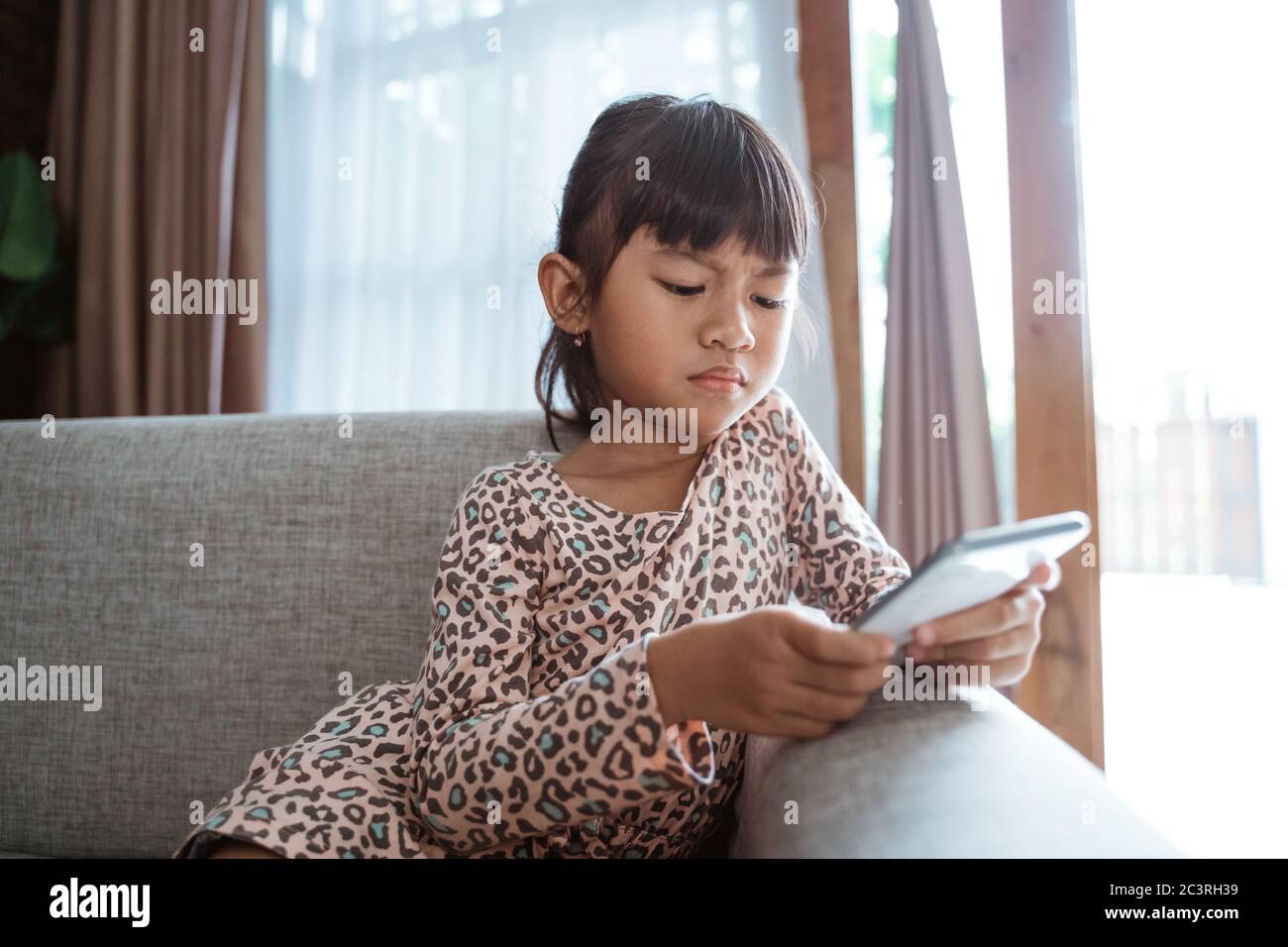 bored child play with mobile phone while staying home Stock Photo - Alamy