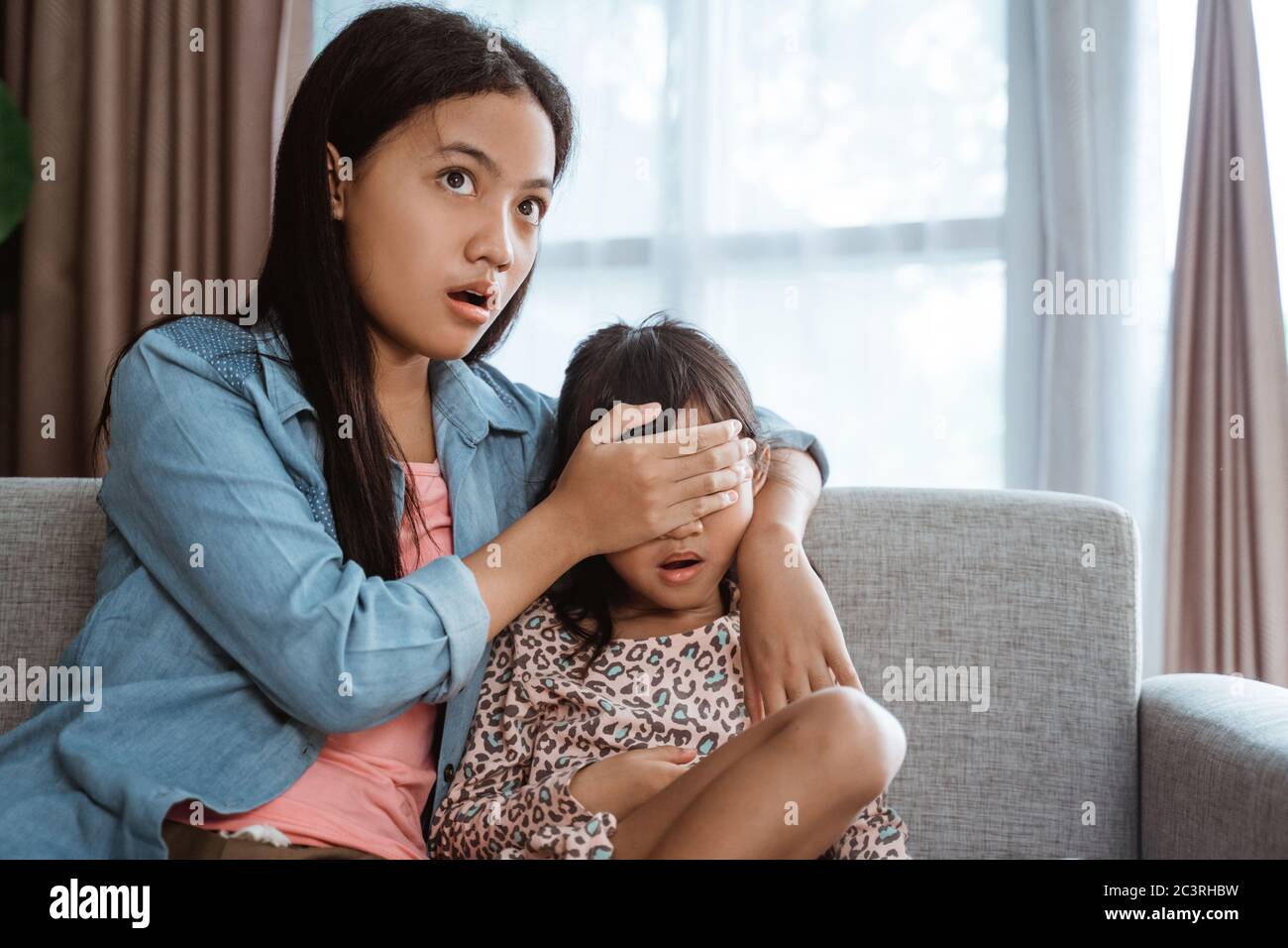 sibling cover her sister's eye while watching scary movie at home Stock ...