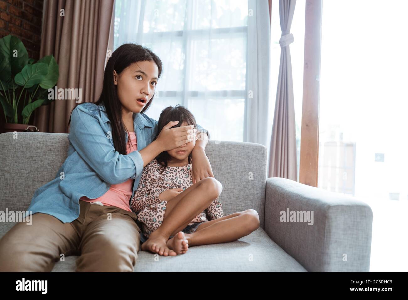 sibling cover her sister's eye while watching scary movie at home Stock ...