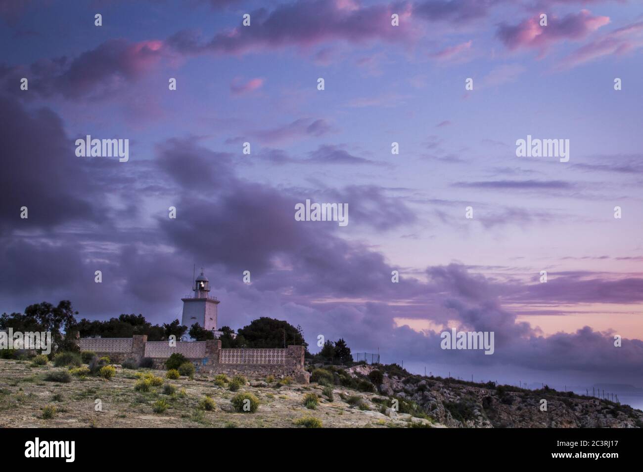 Stone lighthouse on an amazing purple sunset background Stock Photo - Alamy