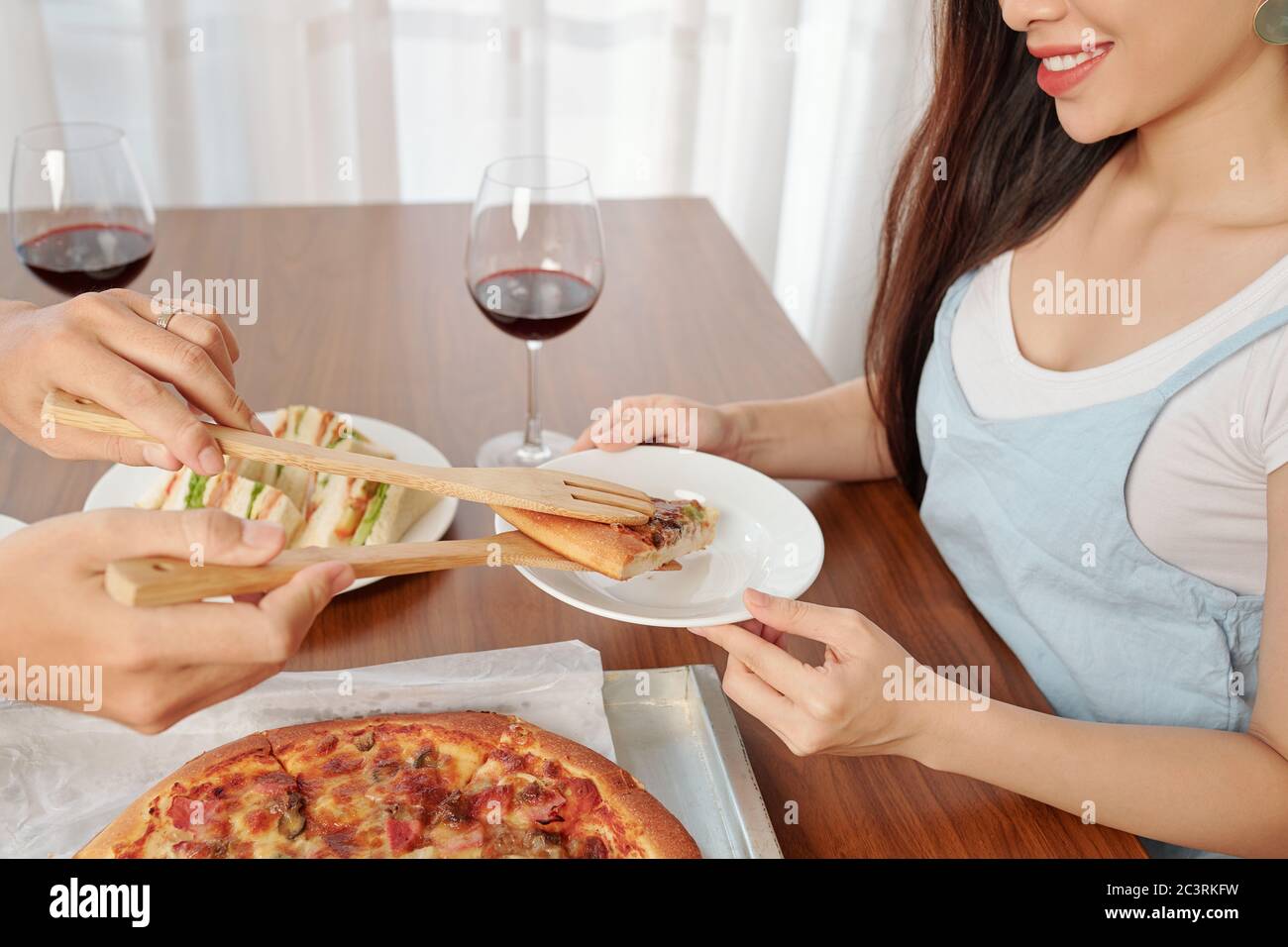 Young man putting a slice of homemade pizza in plate of his wife when ...