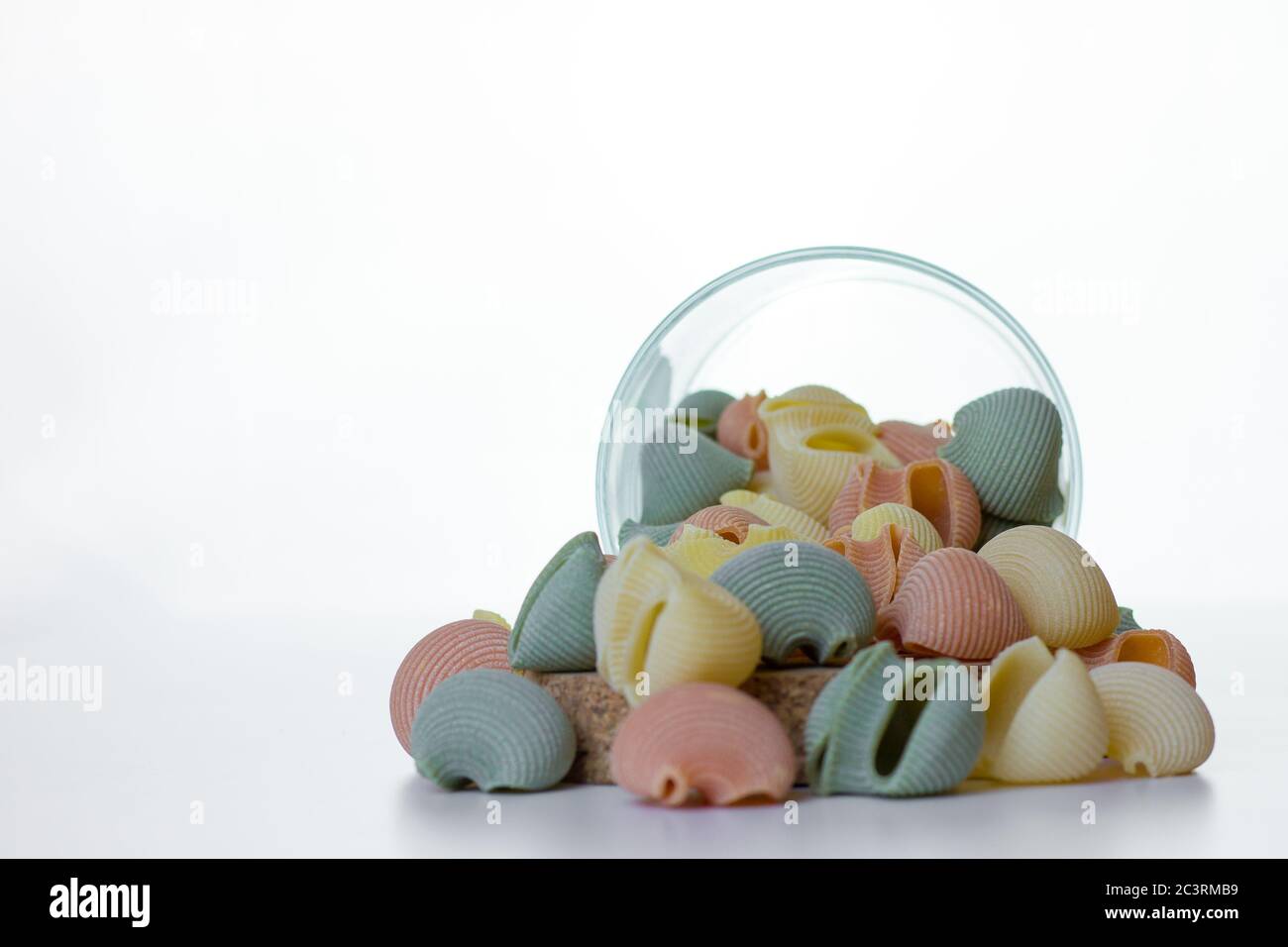 Lot of colorful organic Italian pasta falling from a glass jar isolated ...