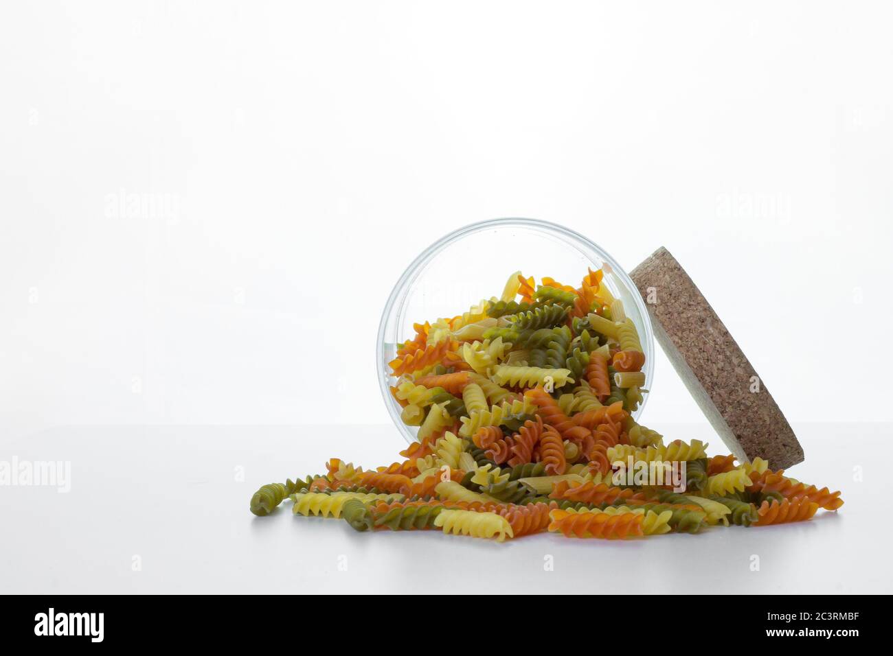 Lot of colorful organic Italian pasta falling from a glass jar isolated ...