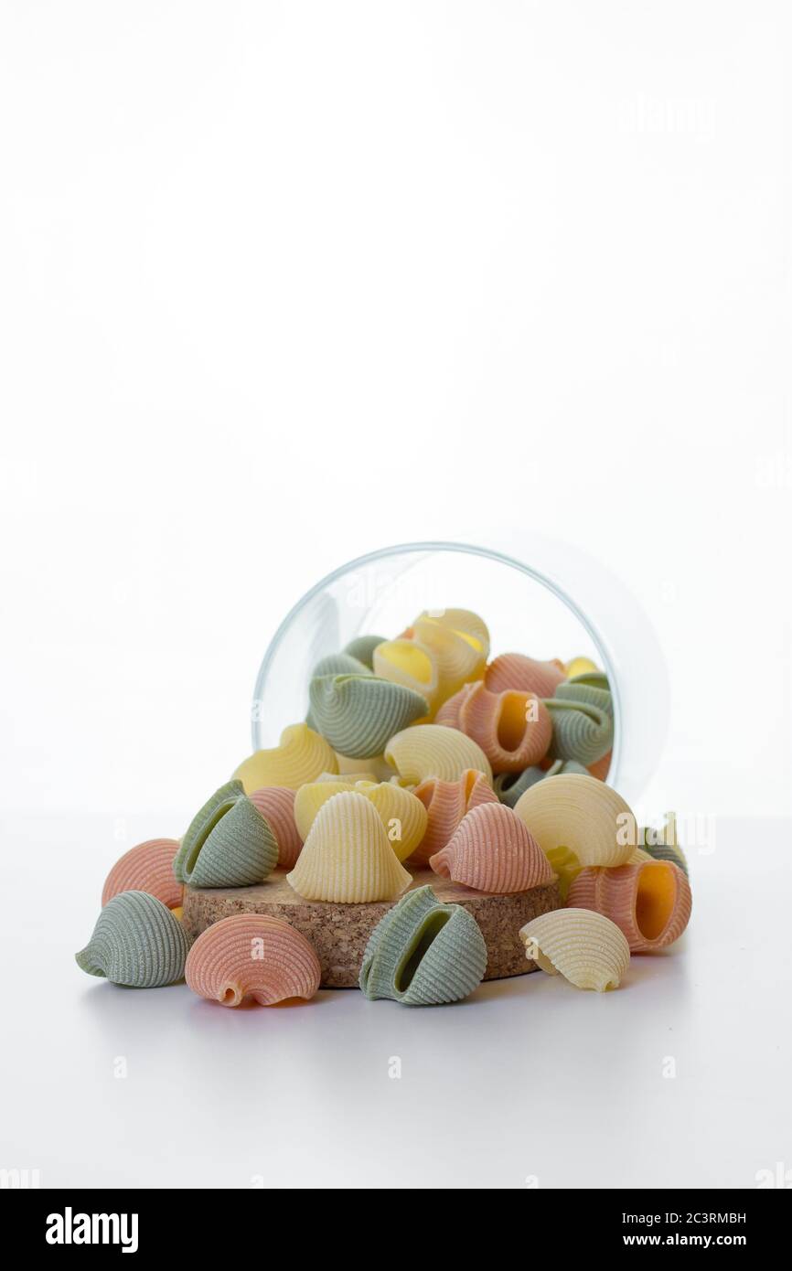Lot of colorful organic Italian pasta falling from a glass jar isolated ...