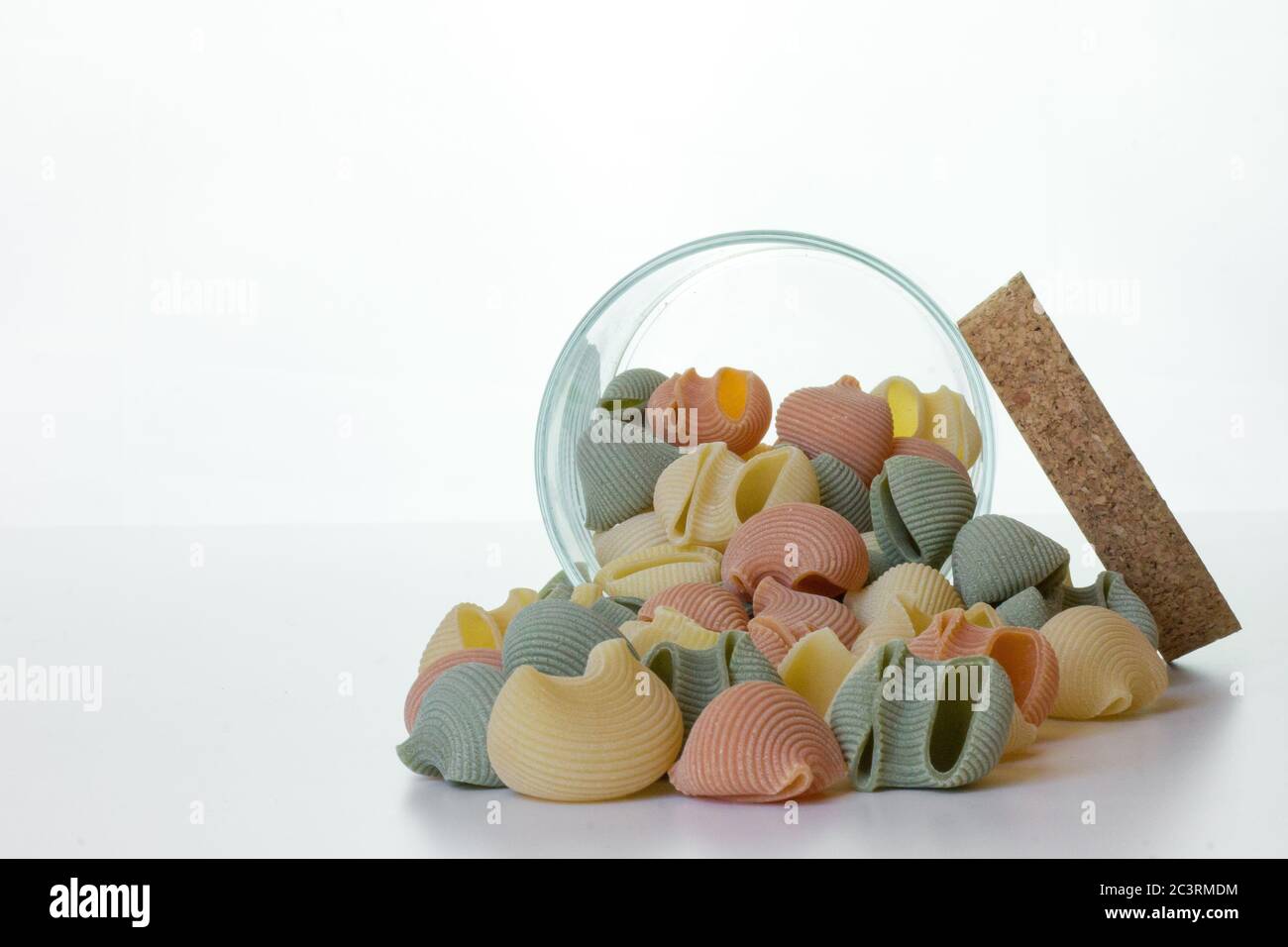 Lot of colorful organic Italian pasta falling from a glass jar isolated ...