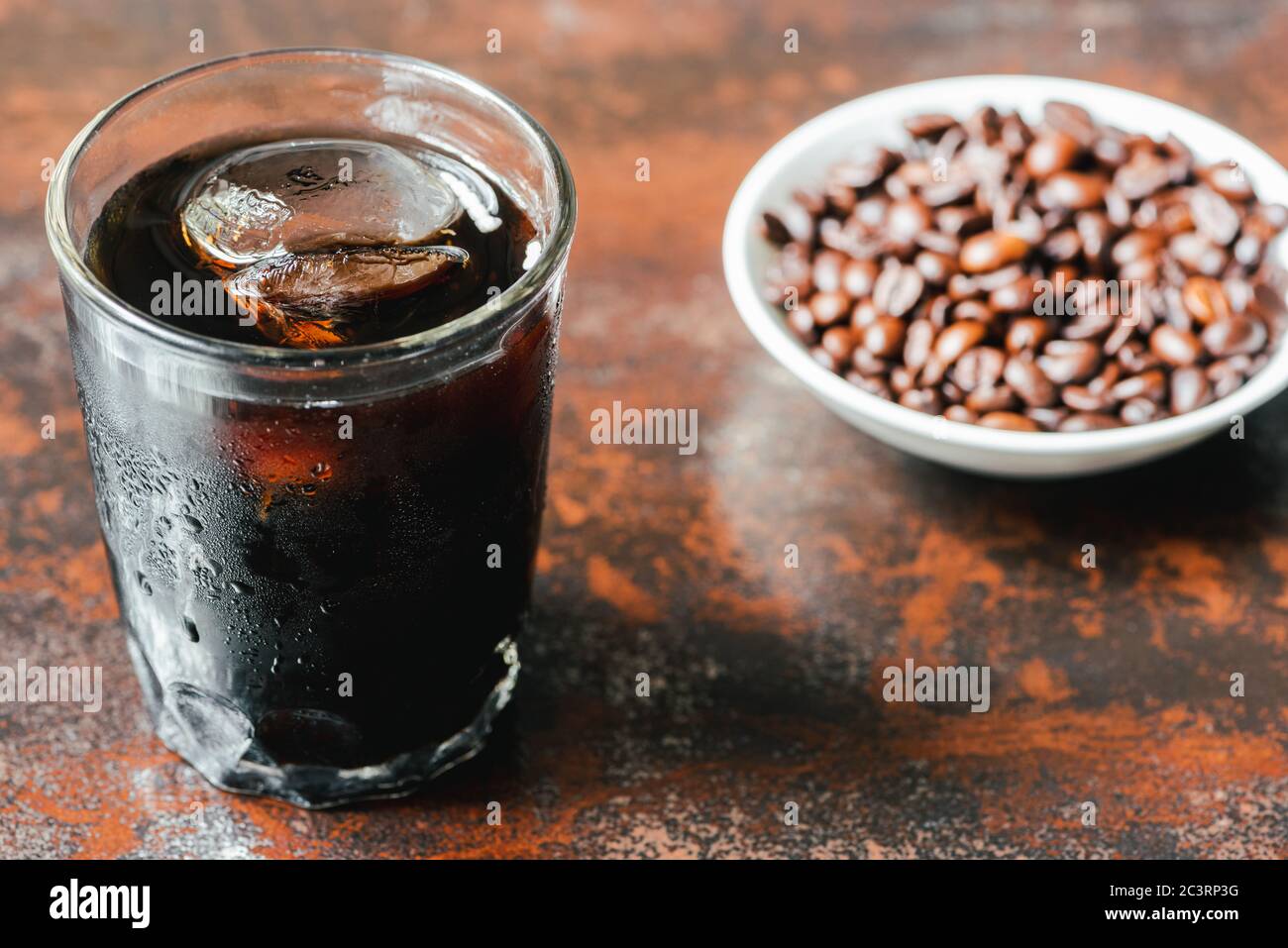 selective focus of cold brew coffee with ice in glass and bottle near ...