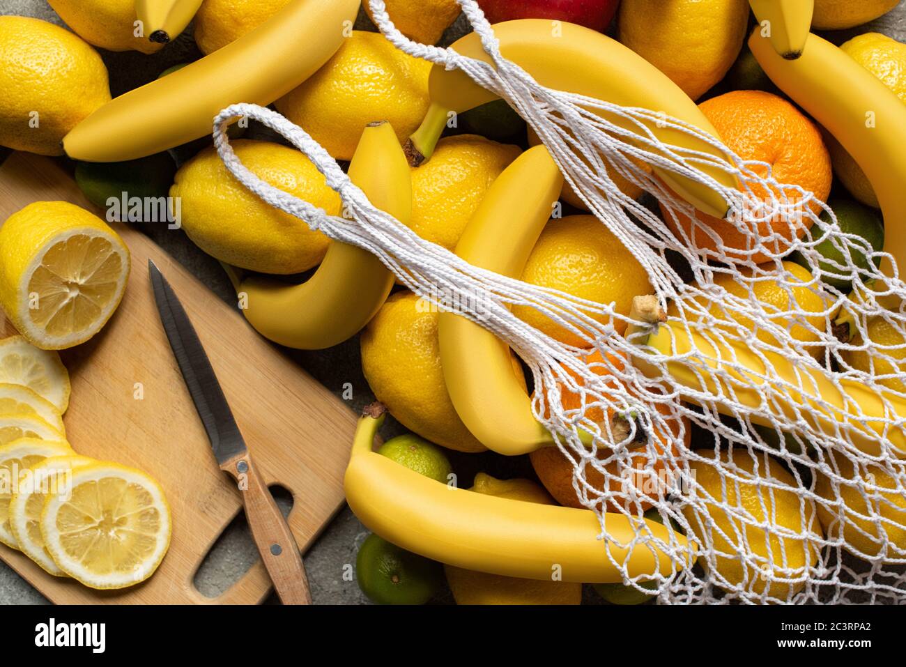 top view of colorful fruits, chopping board with knife and sliced lemon ...
