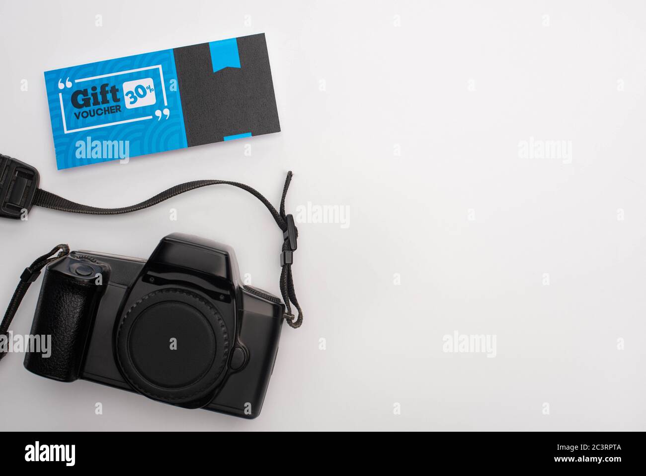 Top view of gift voucher near digital camera on white background with ...