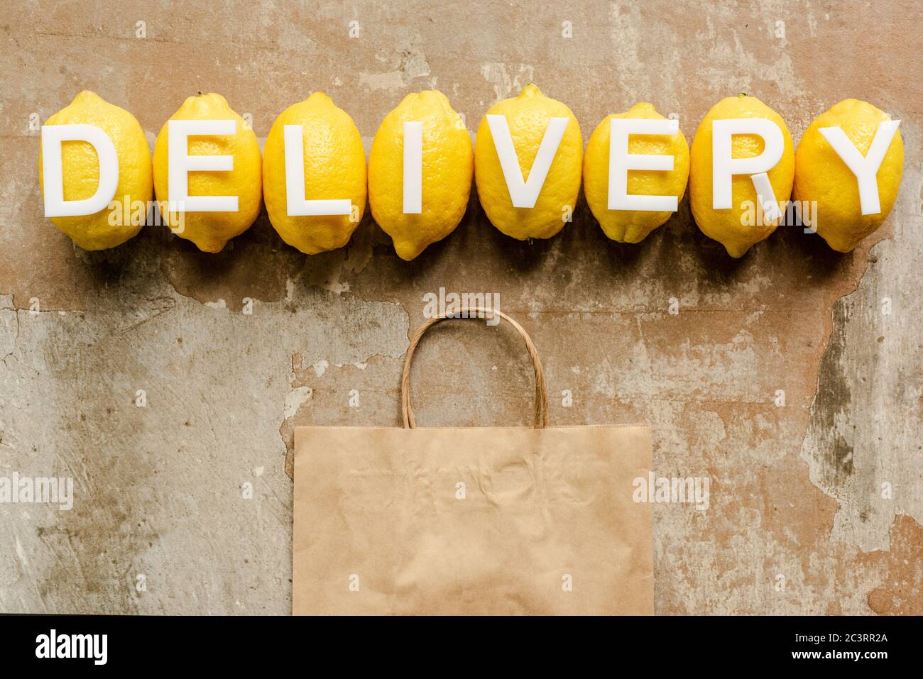 top view of word delivery on lemons near paper bag on weathered surface ...