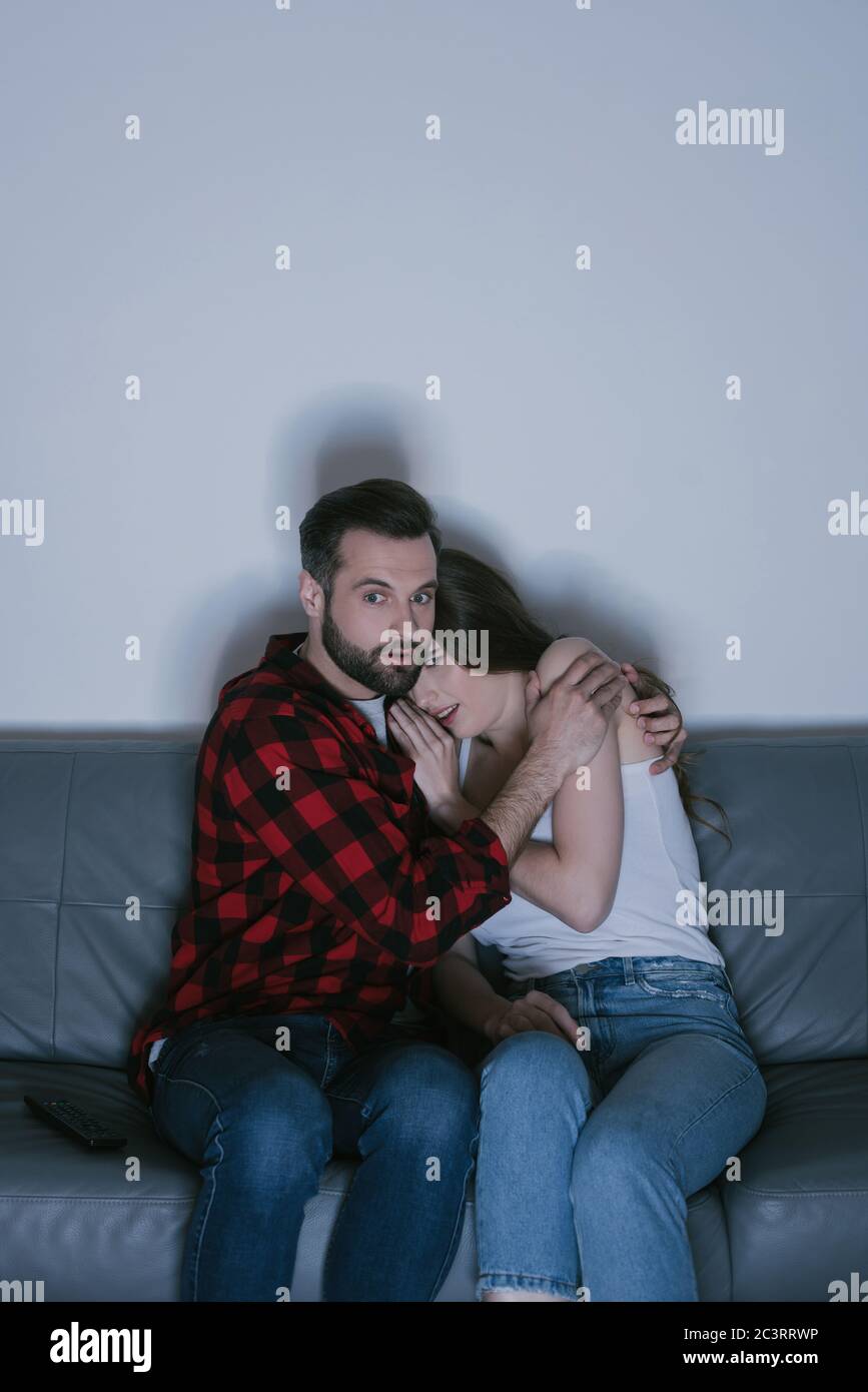 scared man hugging frightened girl while watching movie together at ...