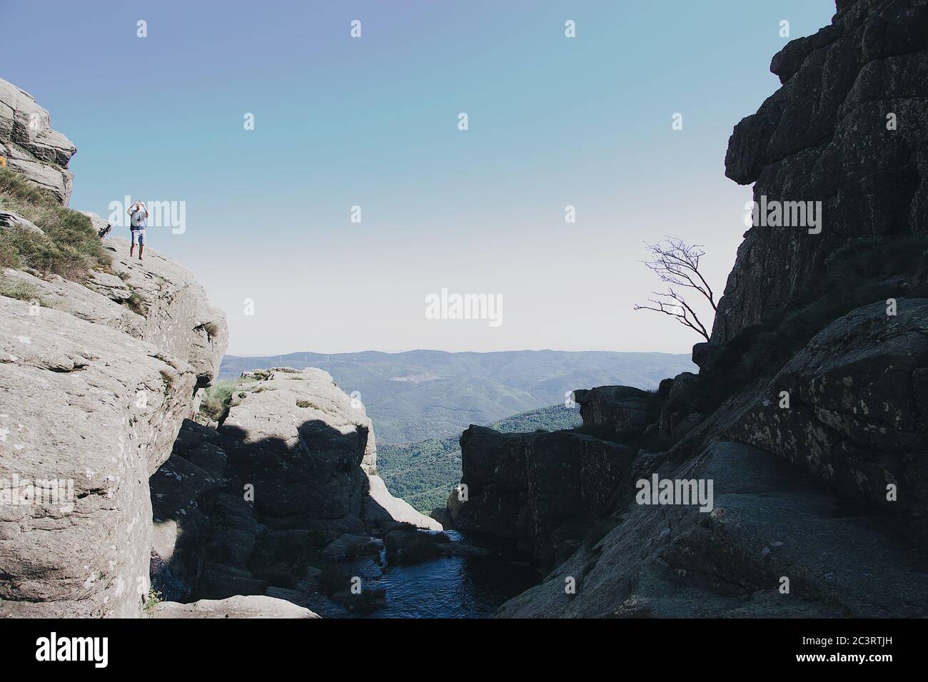 Hiker standing on top of the rocks overlooking a small river and ...