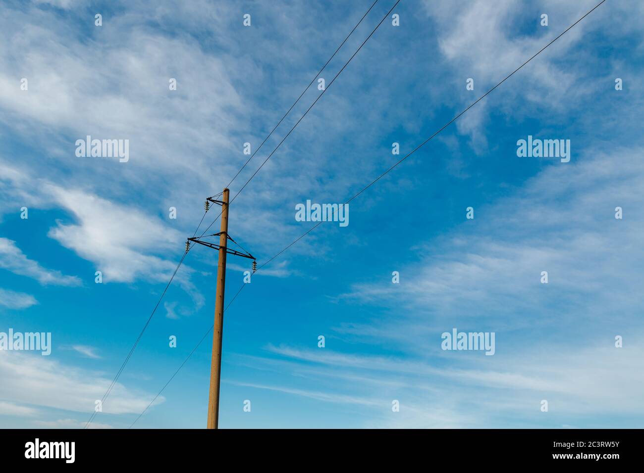 Power line post with electricity cables against a clear sky with white ...