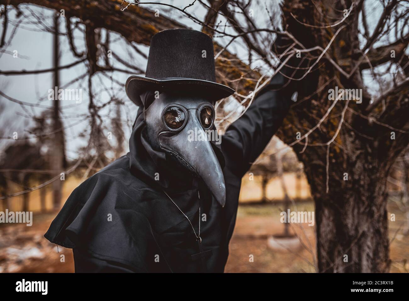 Plague doctor with a cane and a classic dark garb with a cross Stock ...