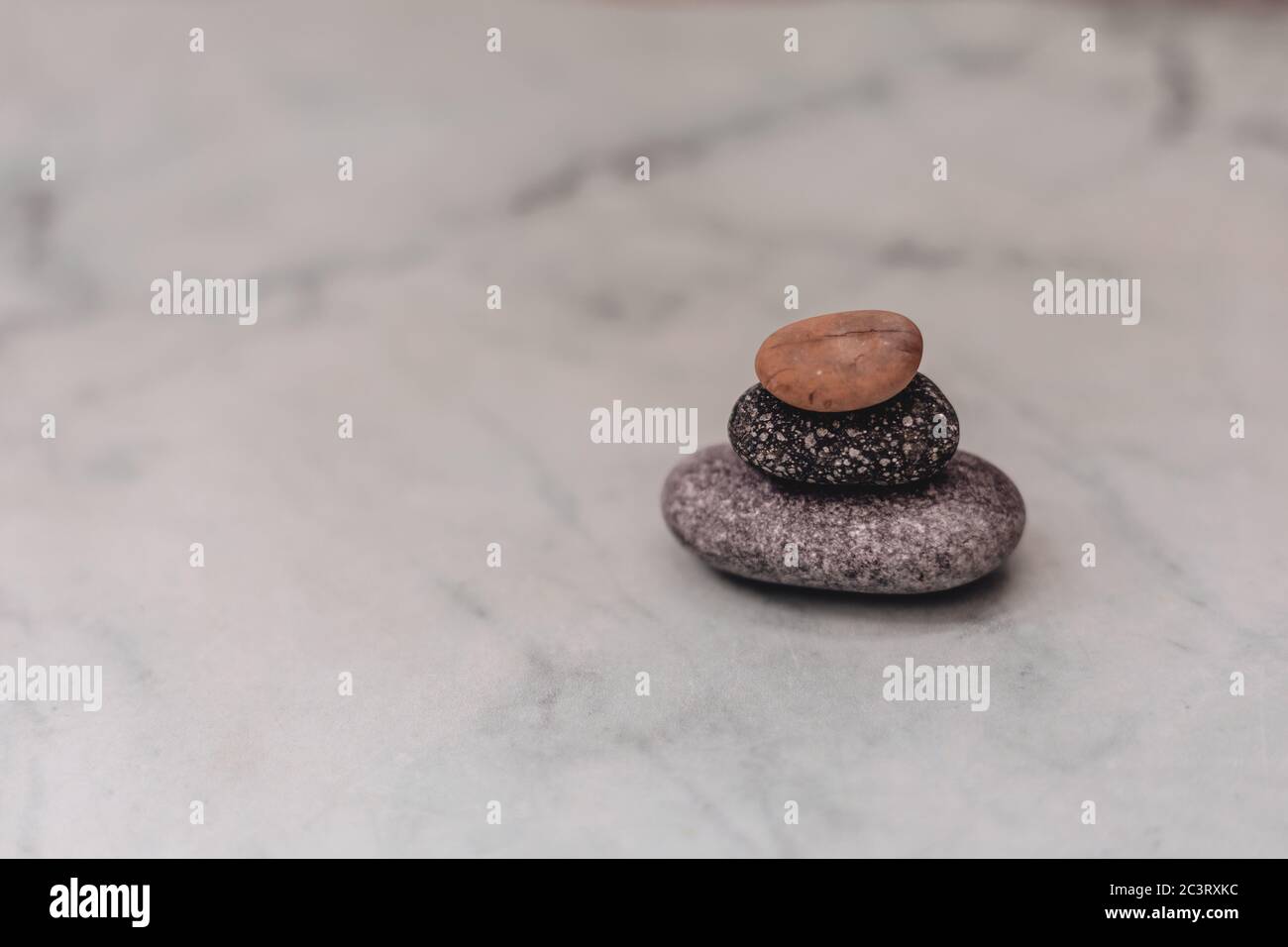 Stone cairn on striped grey white marble background, three stones tower, simple poise stones ...