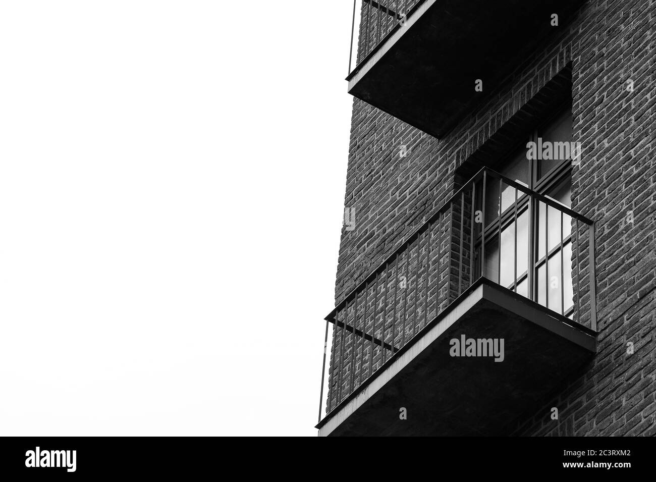 Grayscale shot of a brick building facade on a white sky background ...