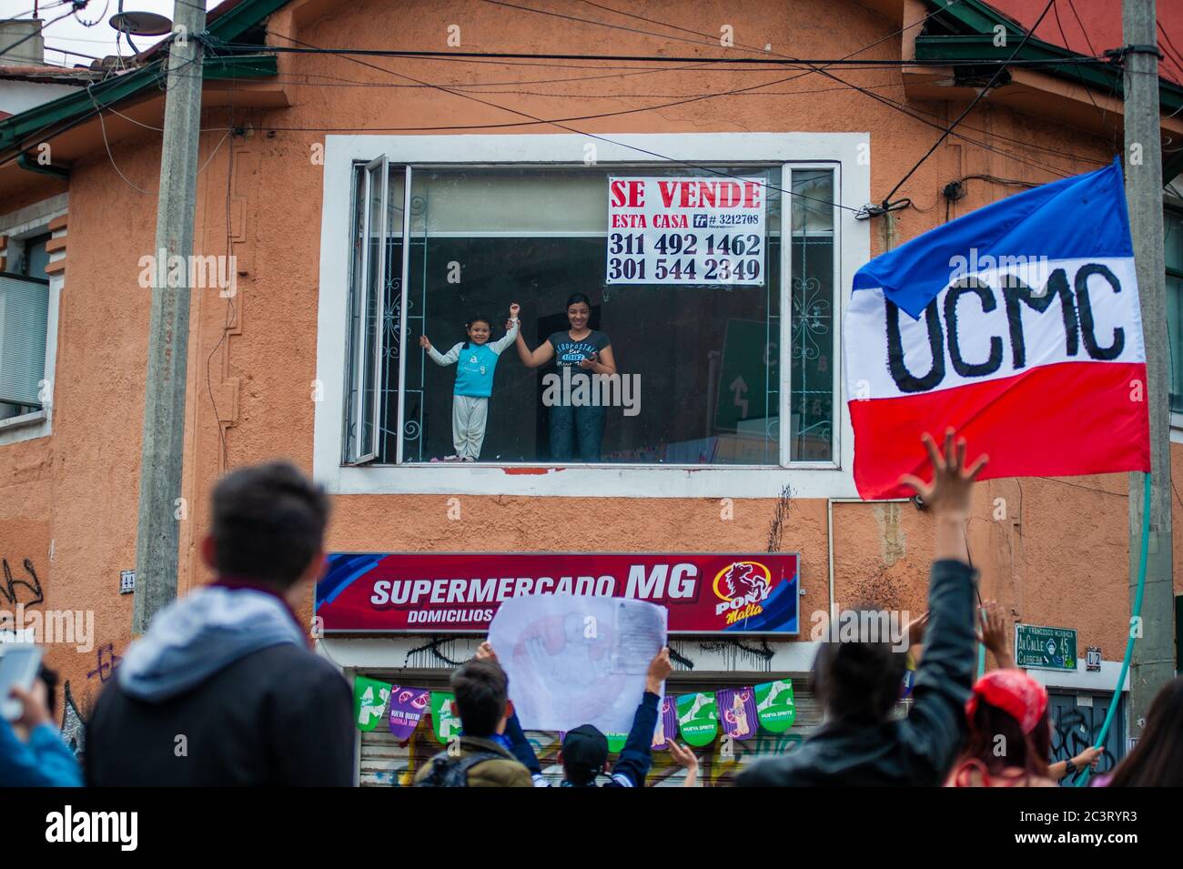 Mom and daughter watch protesters from their house window on the street ...