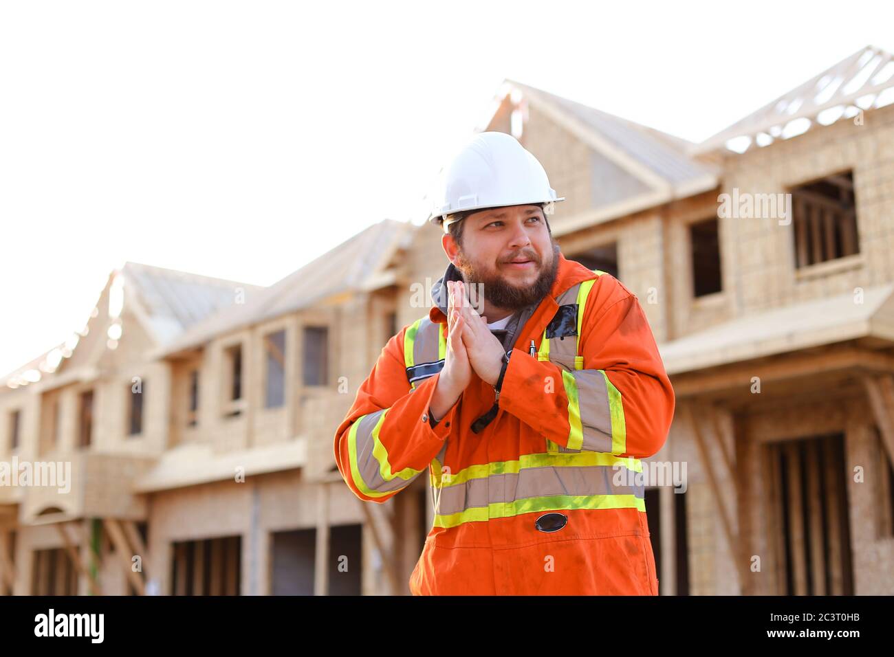 Male foreman thinking on construction site with building in background ...
