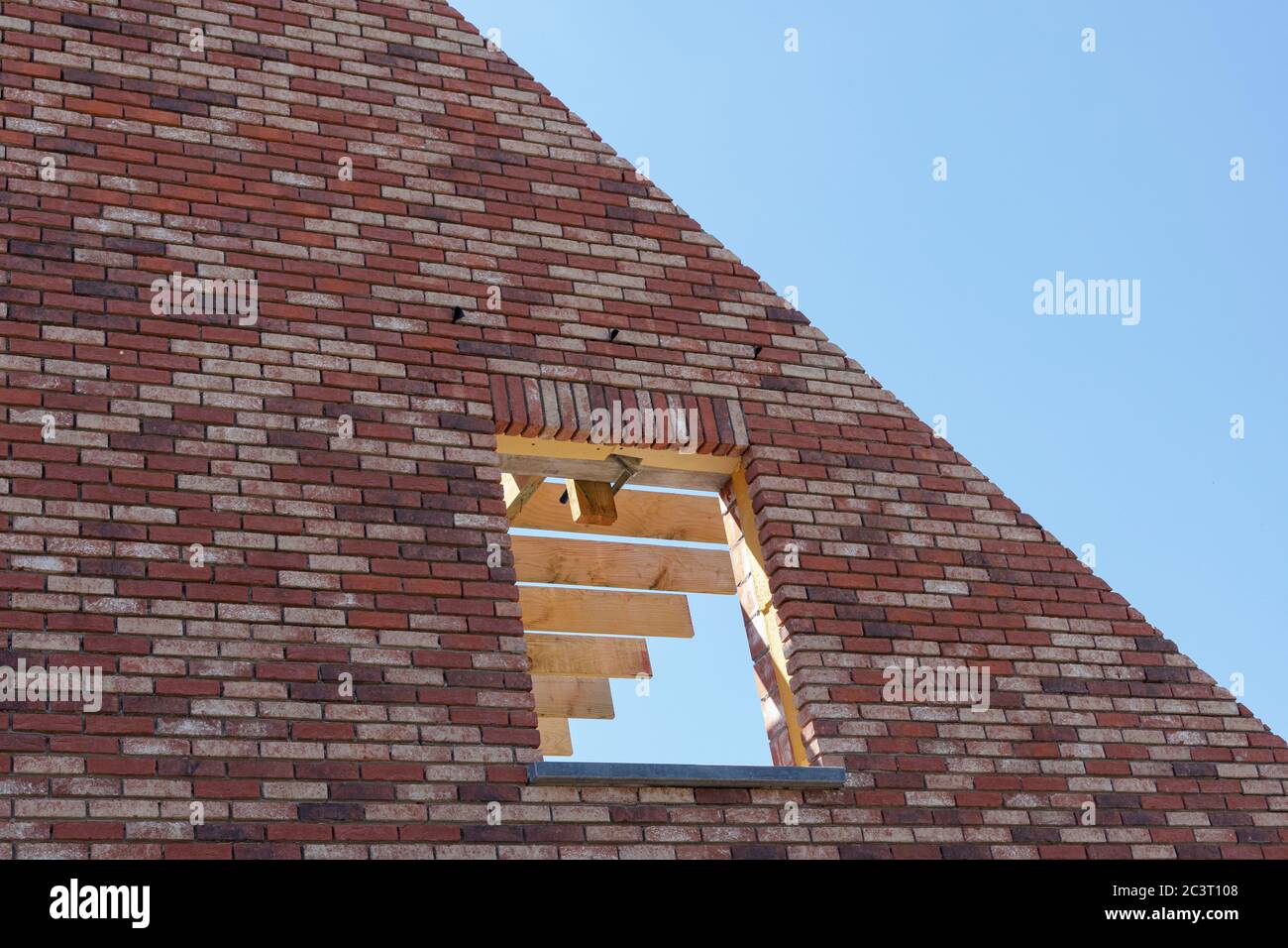 Side of a new house under construction with window opening and wooden ...